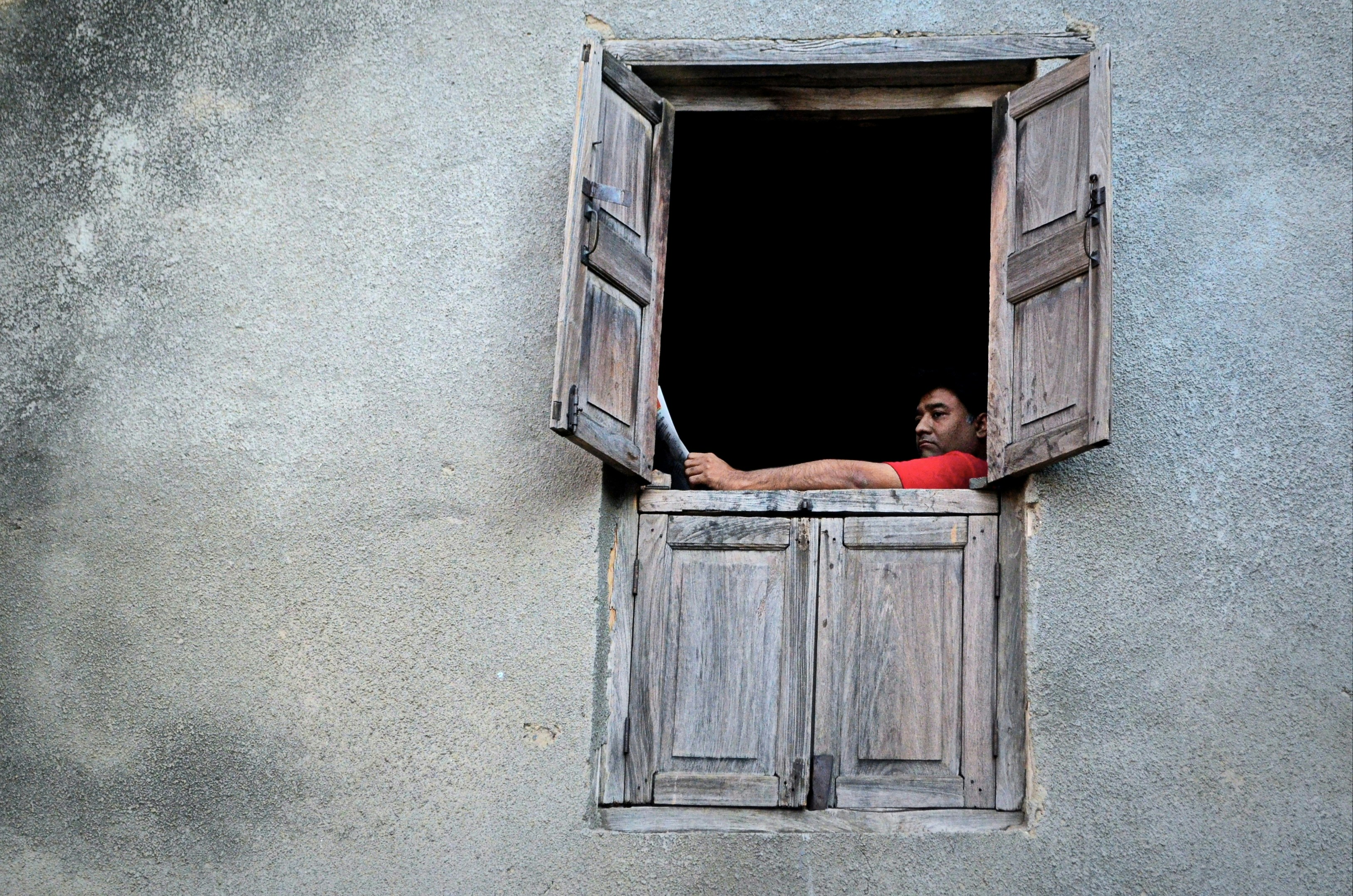 Red Sleeve at a Weathered Window: A Quiet Reach from the Wall