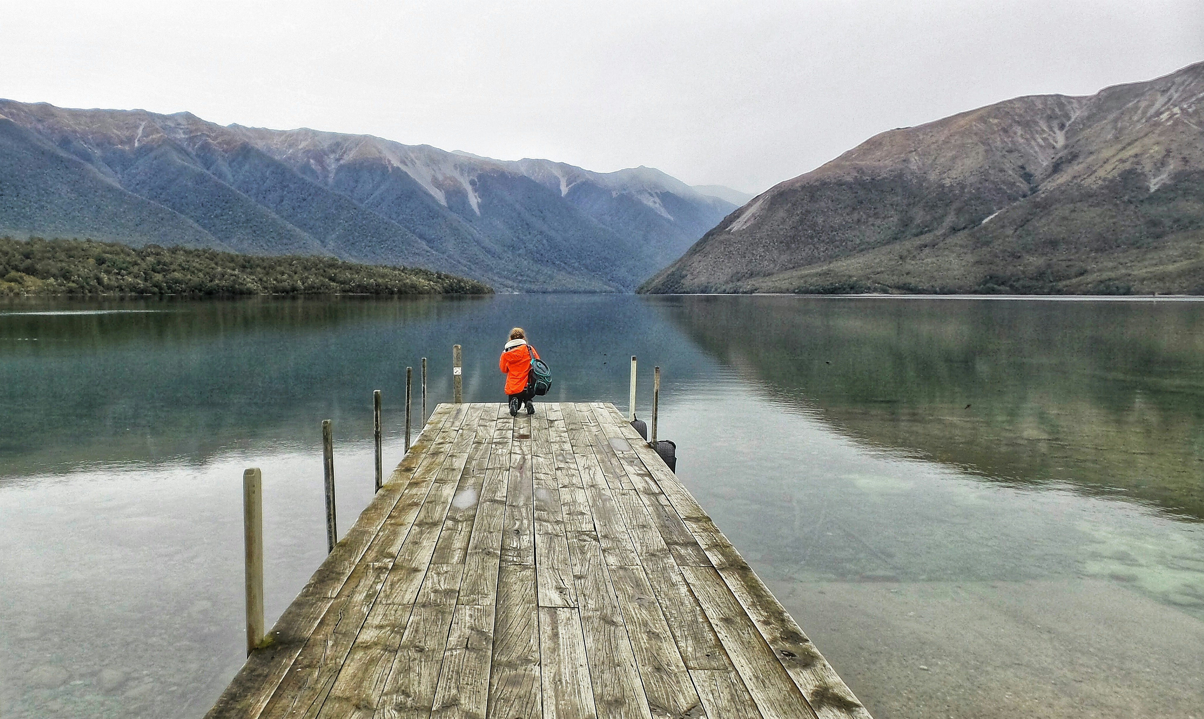 Fisherman at the End of the Wooden Pier Against a Mountain–Lake Panorama