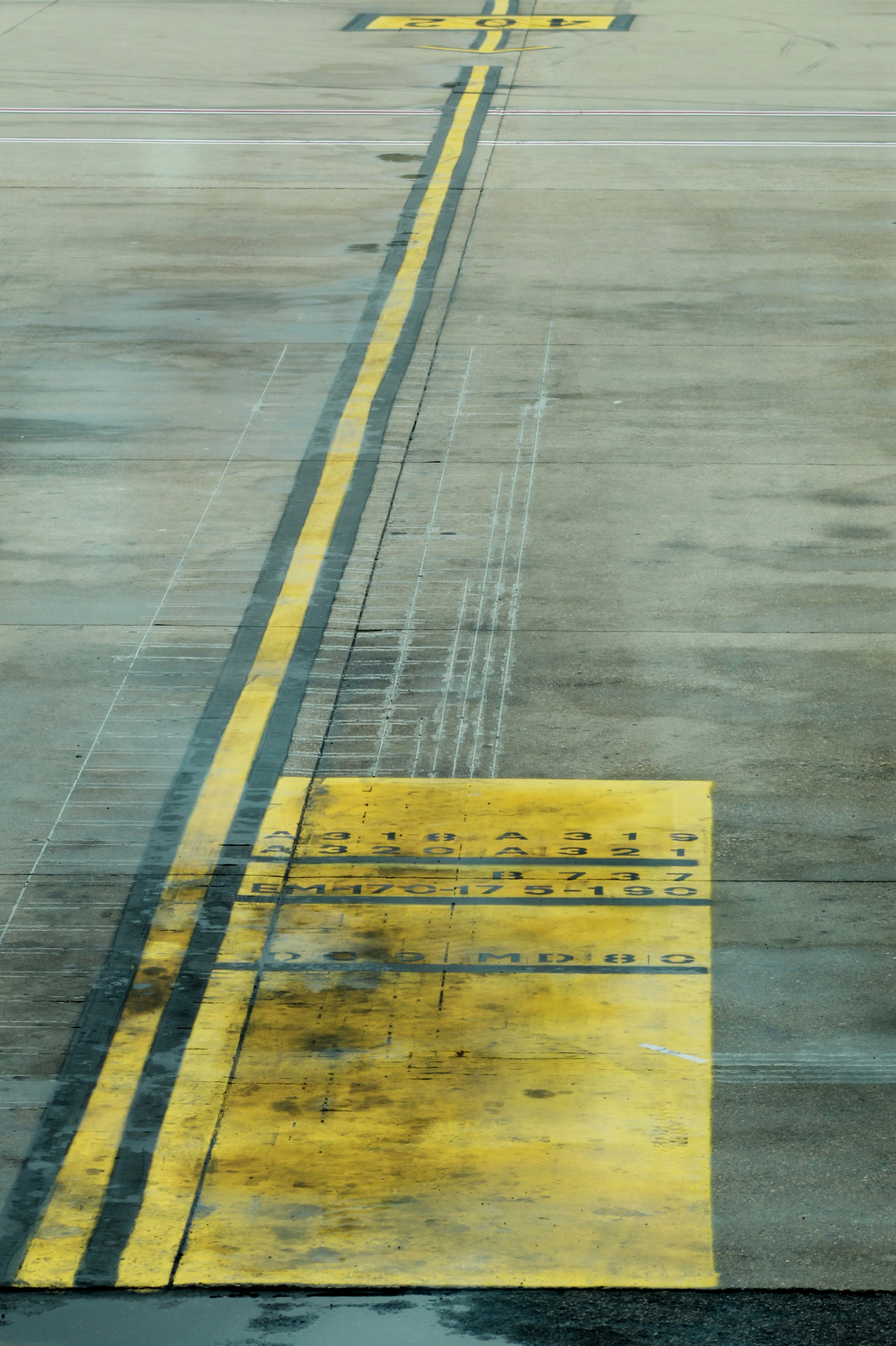 Yellow markings on an airport runway guide aircraft movement, showcasing wear and tear from frequent use.