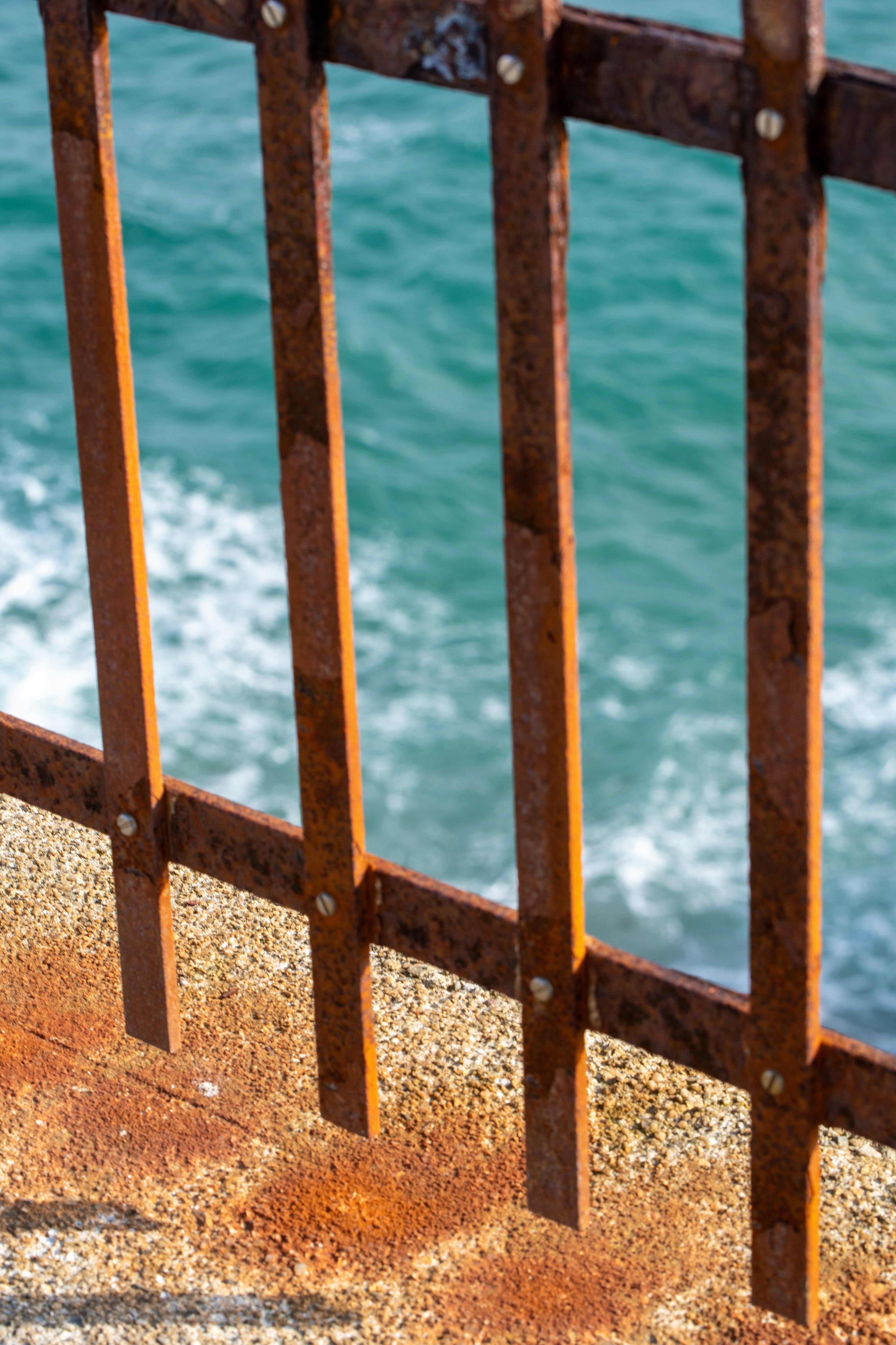 A rusty gate in front of the blue ocean in Cornwall, UK.