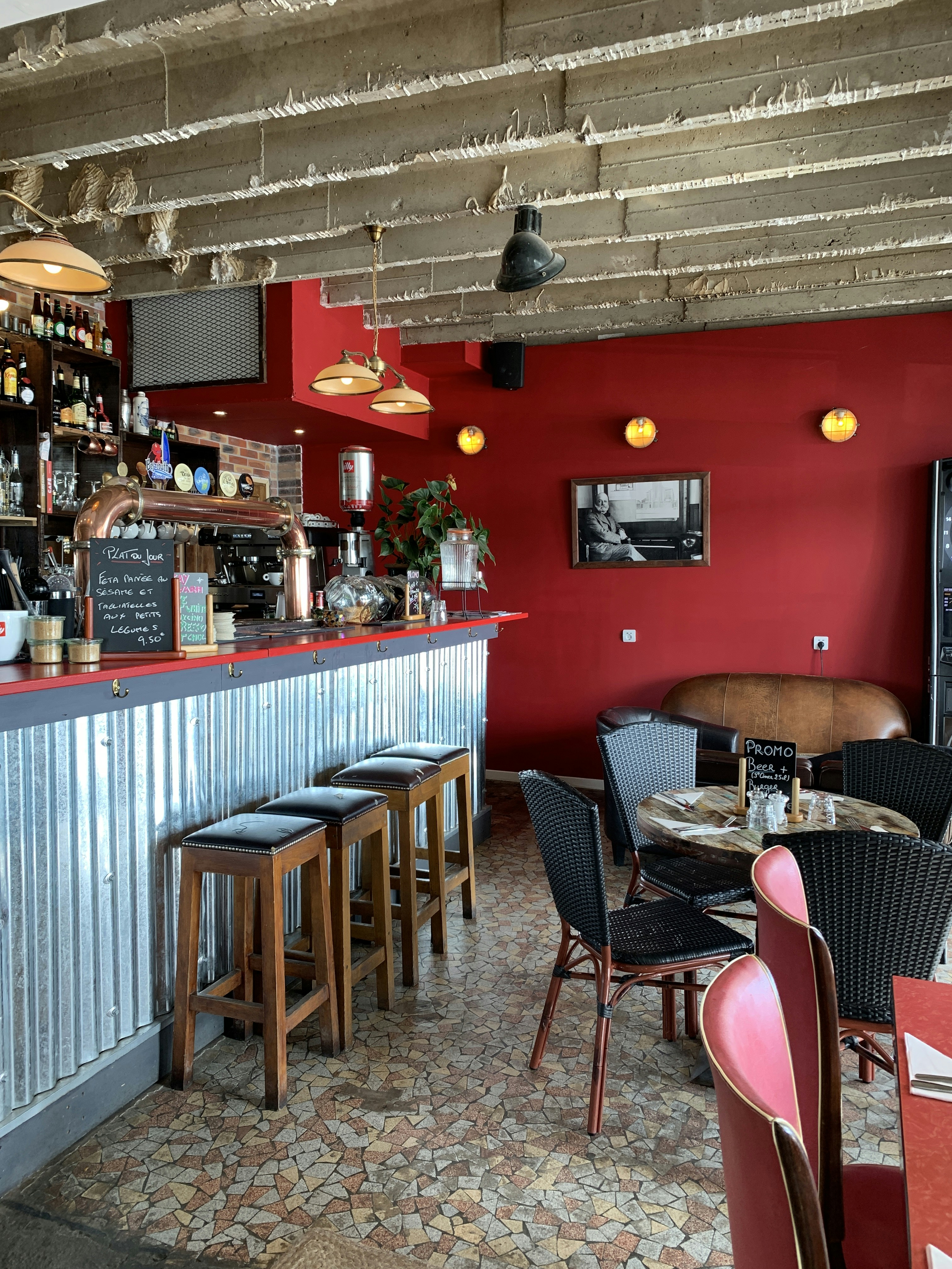 Cozy bar interior featuring a polished counter, stylish seating, and vibrant red walls adorned with decorative lighting. A warm atmosphere invites relaxation.
