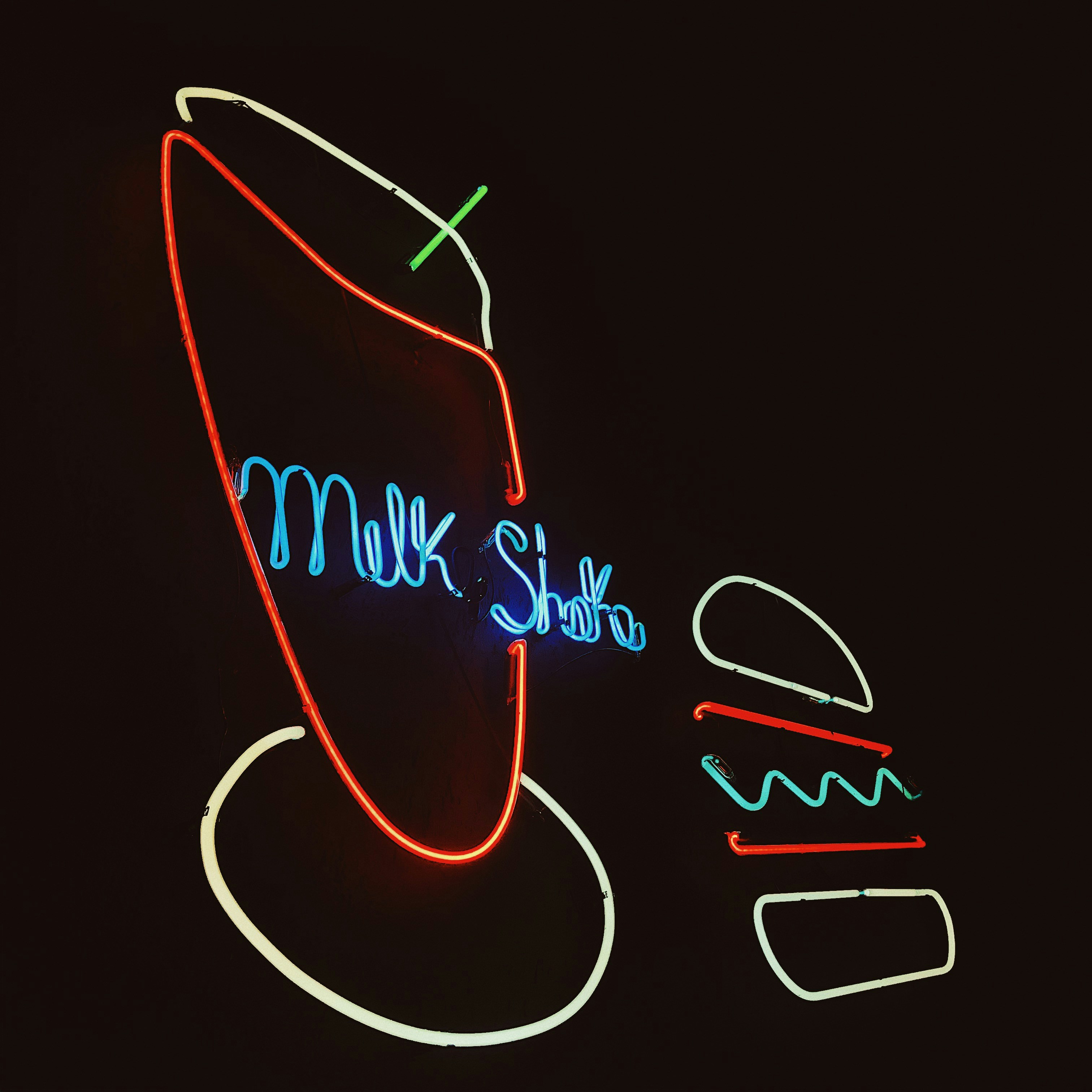 Neon Milk Shake Sign: Red Glass Silhouette with Blue Script in Night