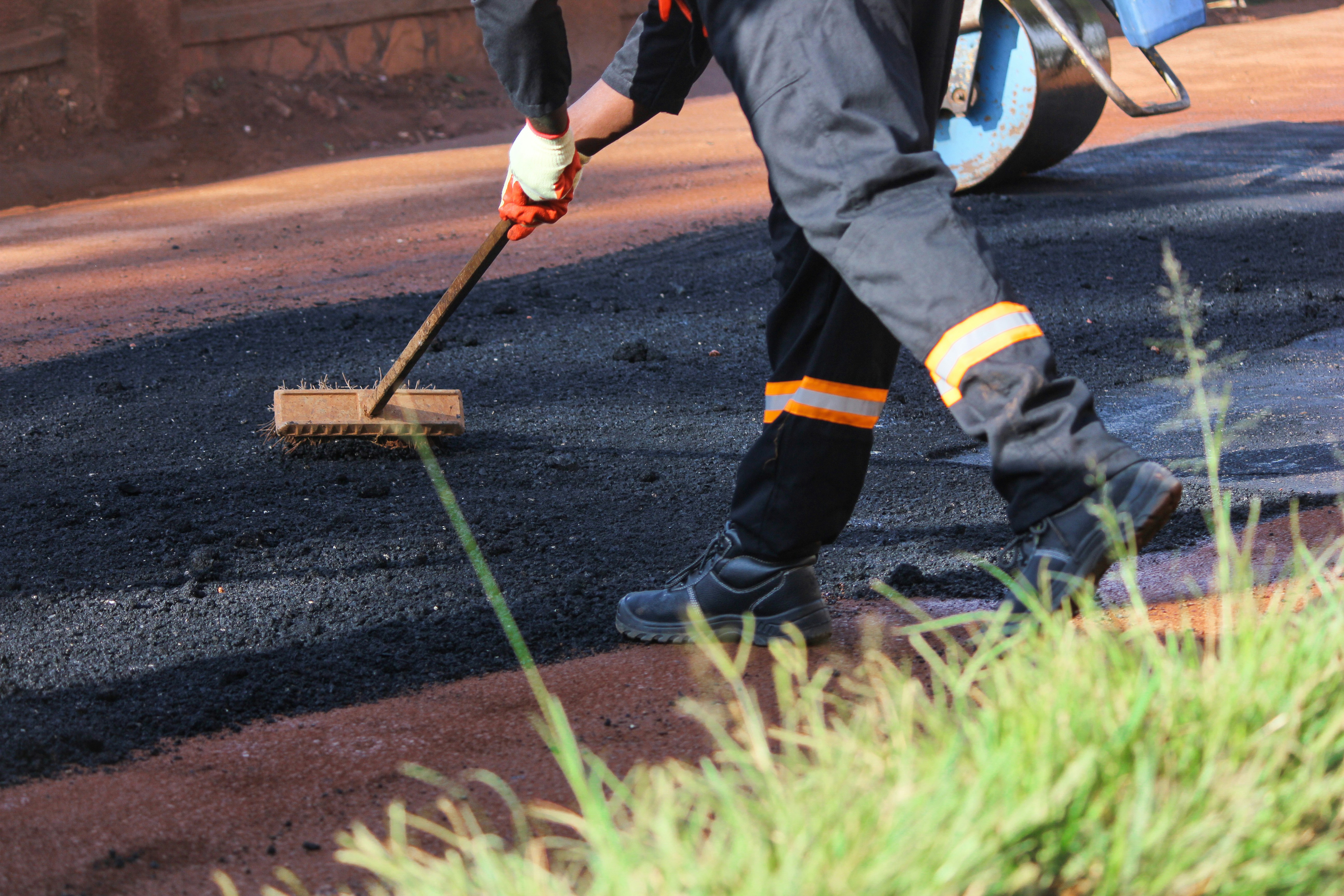 Edge Sweep on Fresh Asphalt: A Roadworker in Ground-Level Focus