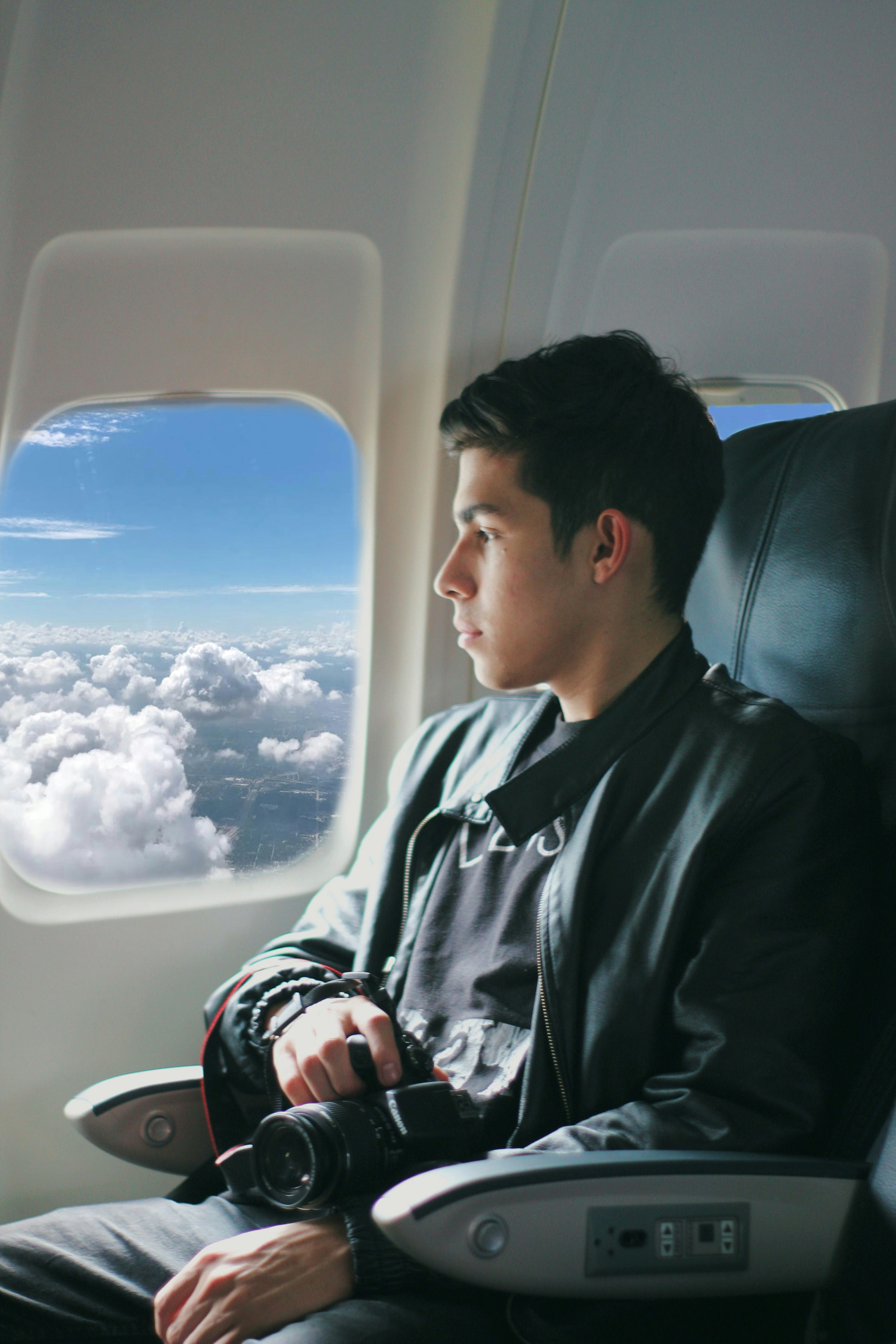 A man sitting in an airplane looking out the window photo – Free Grey ...