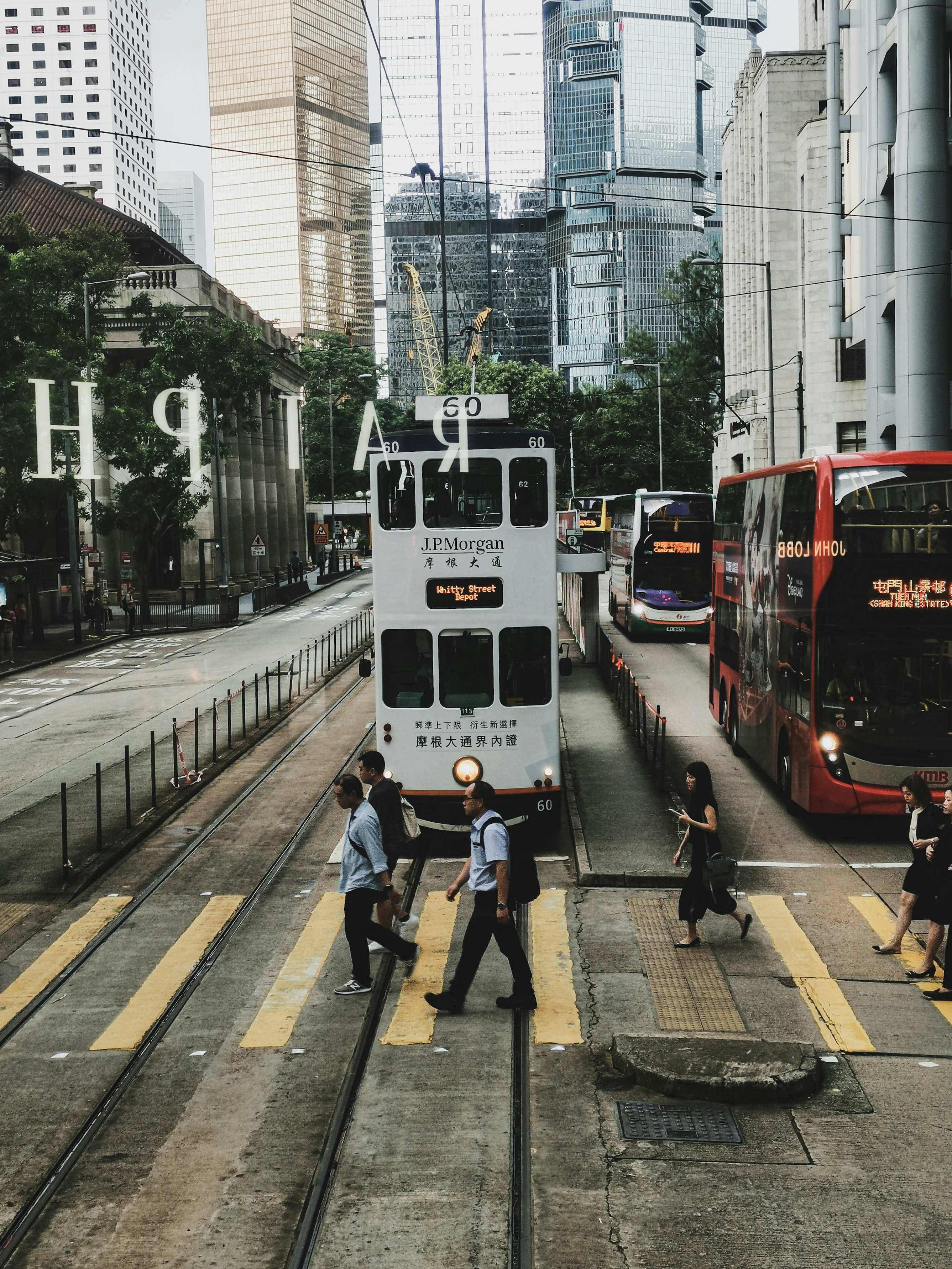 A group of people crossing a street in front of a double decker bus ...