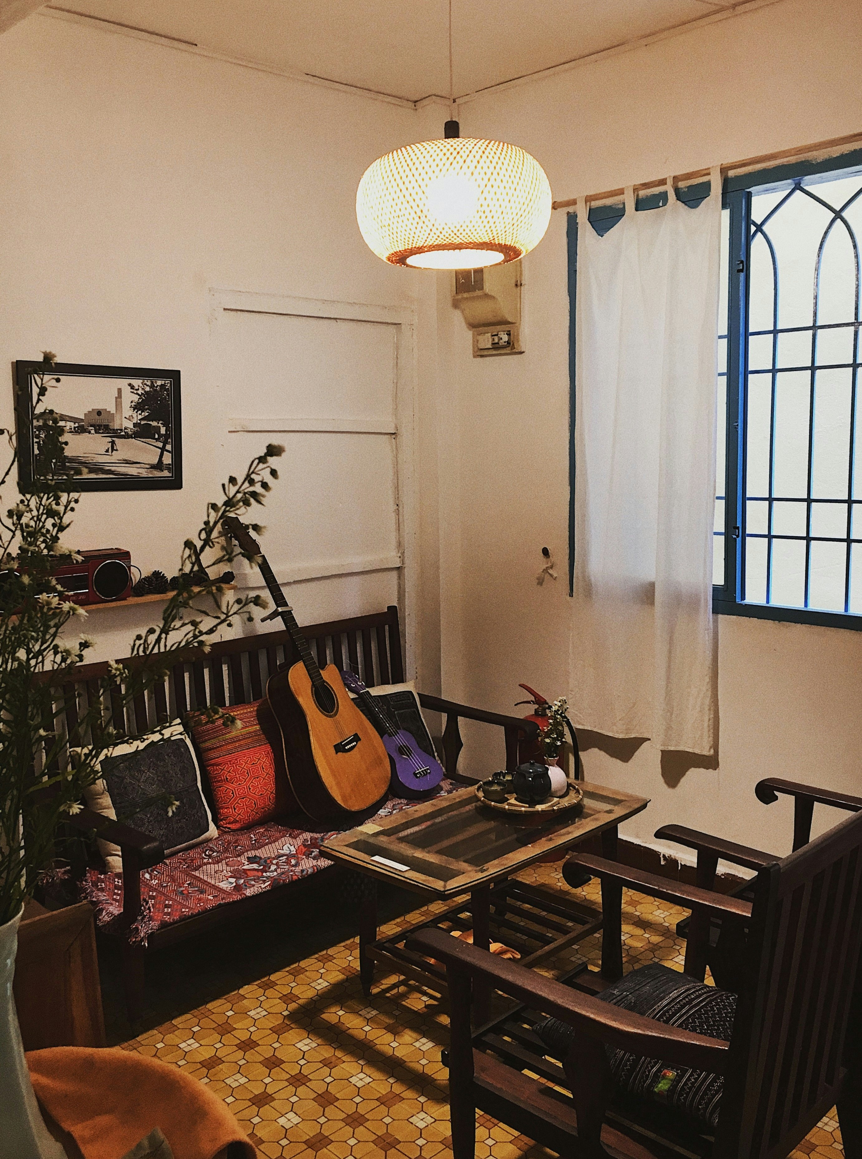 Guitar on a Cushioned Sofa Beneath a Woven Pendant Light