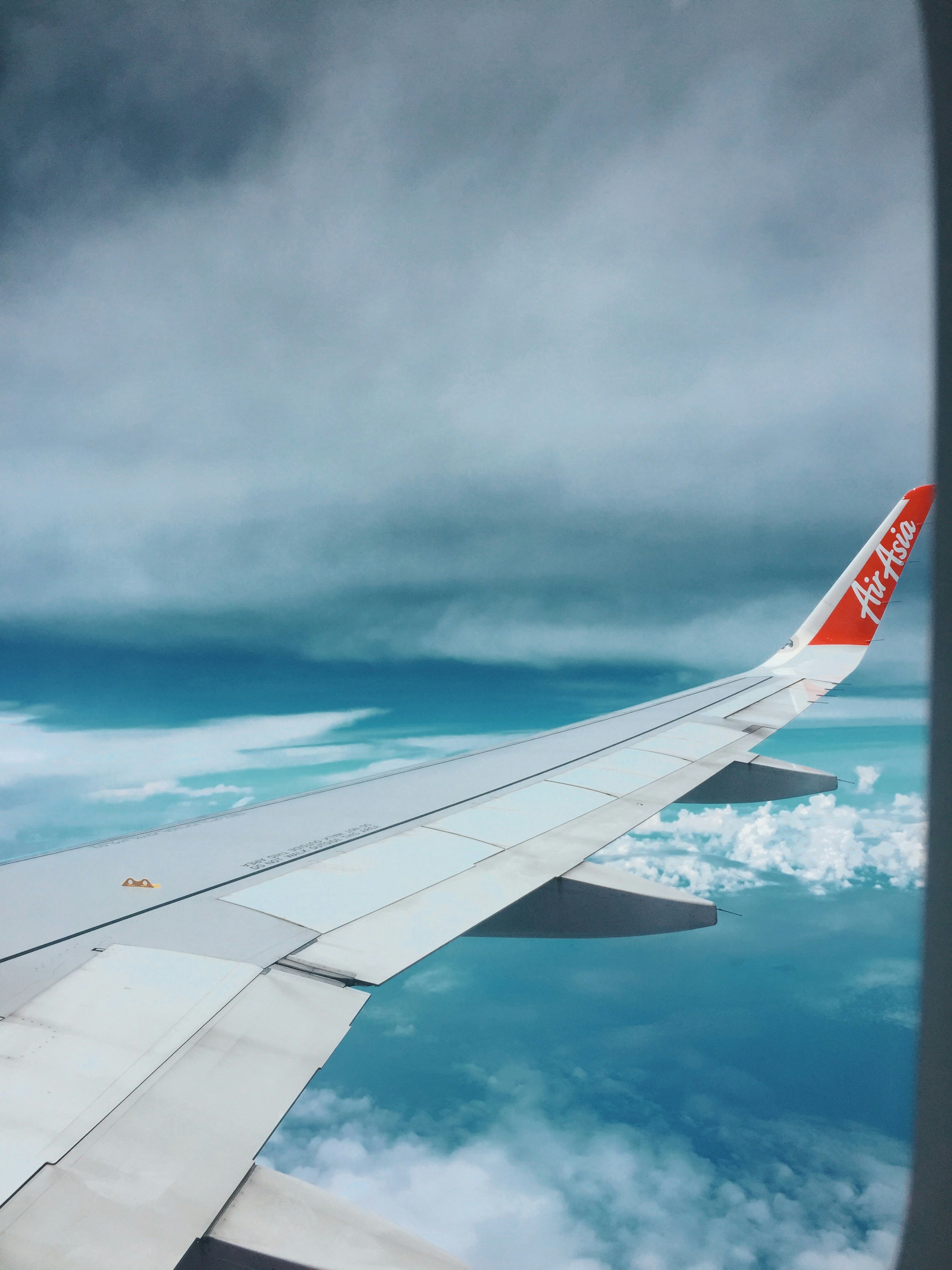 Wingtip Over Turquoise Skies: A Window View Above the Clouds