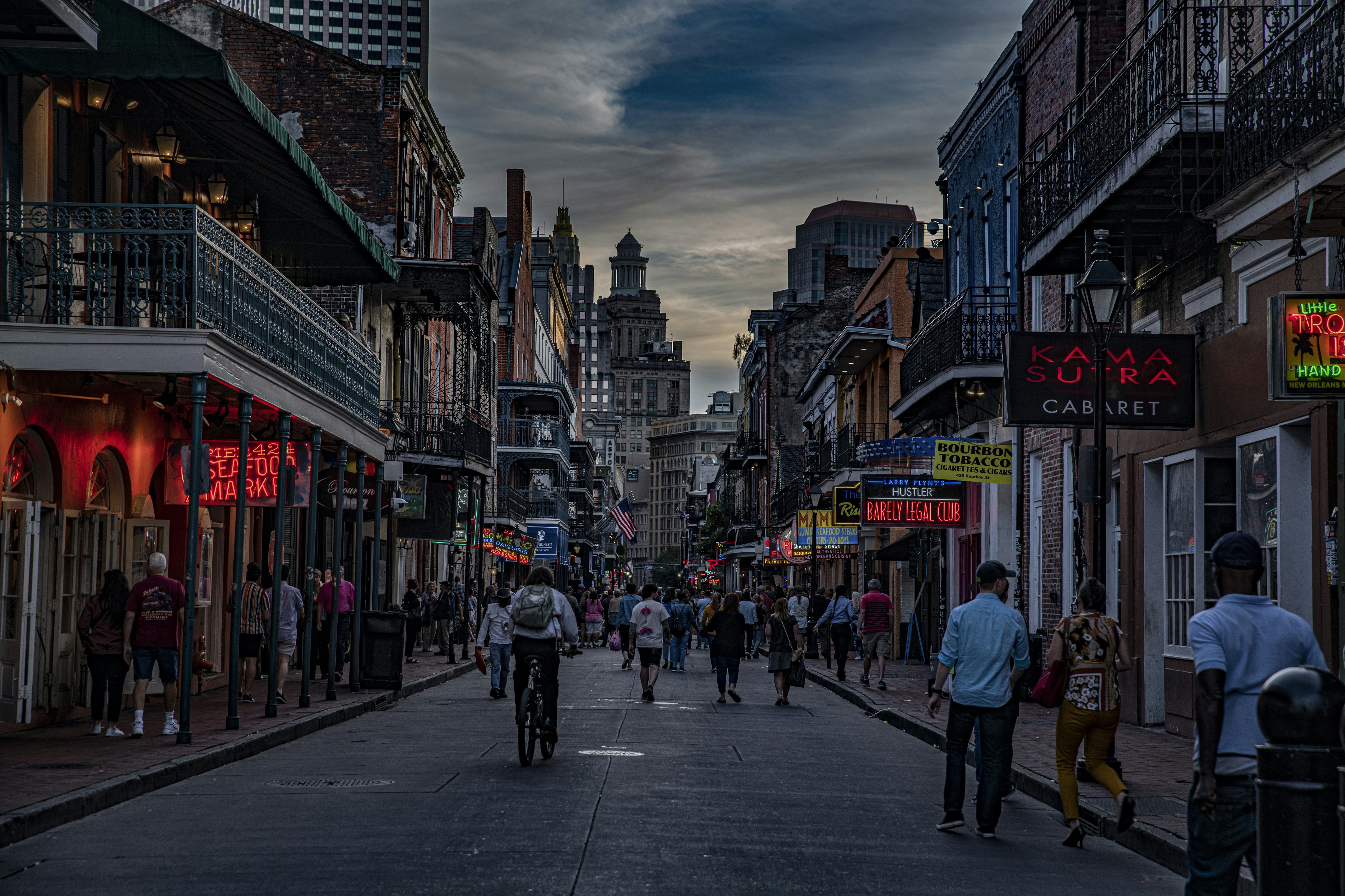 Bustling street scene in the French Quarter with vibrant neon signs and pedestrians enjoying the nightlife. The atmosphere captures the lively essence of New Orleans.