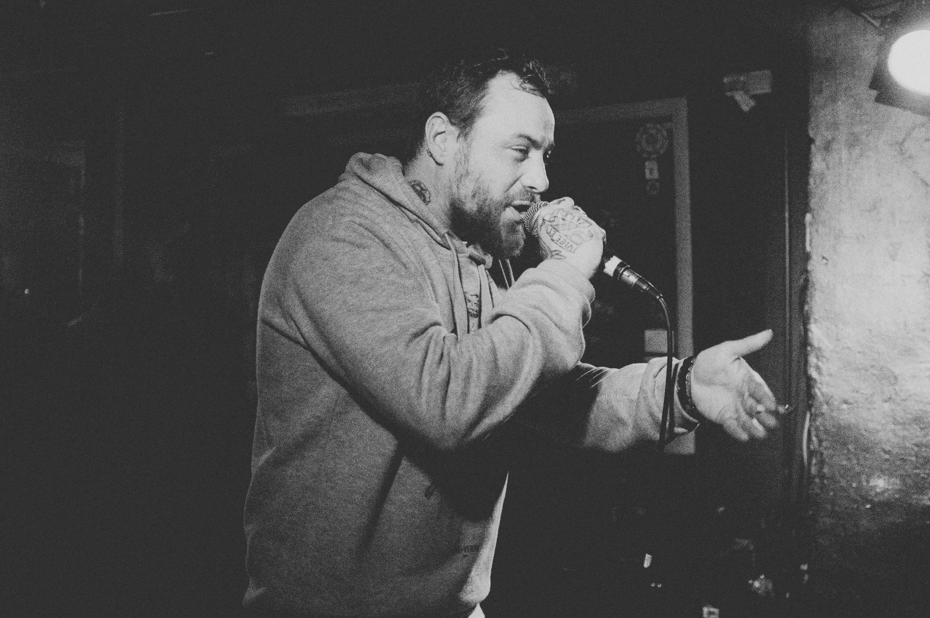 Black and white photo of a man passionately performing with a microphone on stage.
