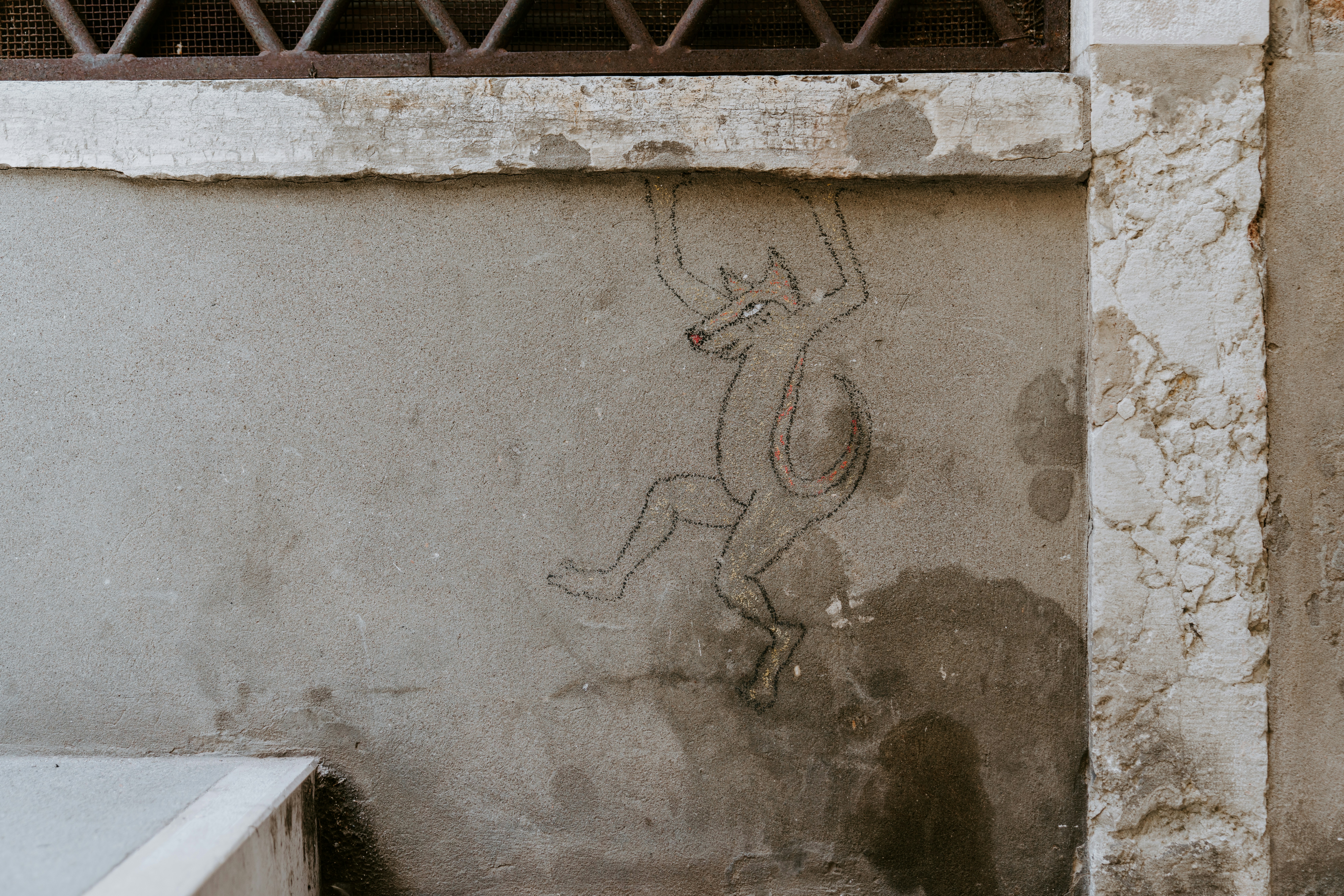 A playful mural of a dancing figure, possibly a fox, painted on a weathered wall. The artwork contrasts with the surrounding textures and colors.