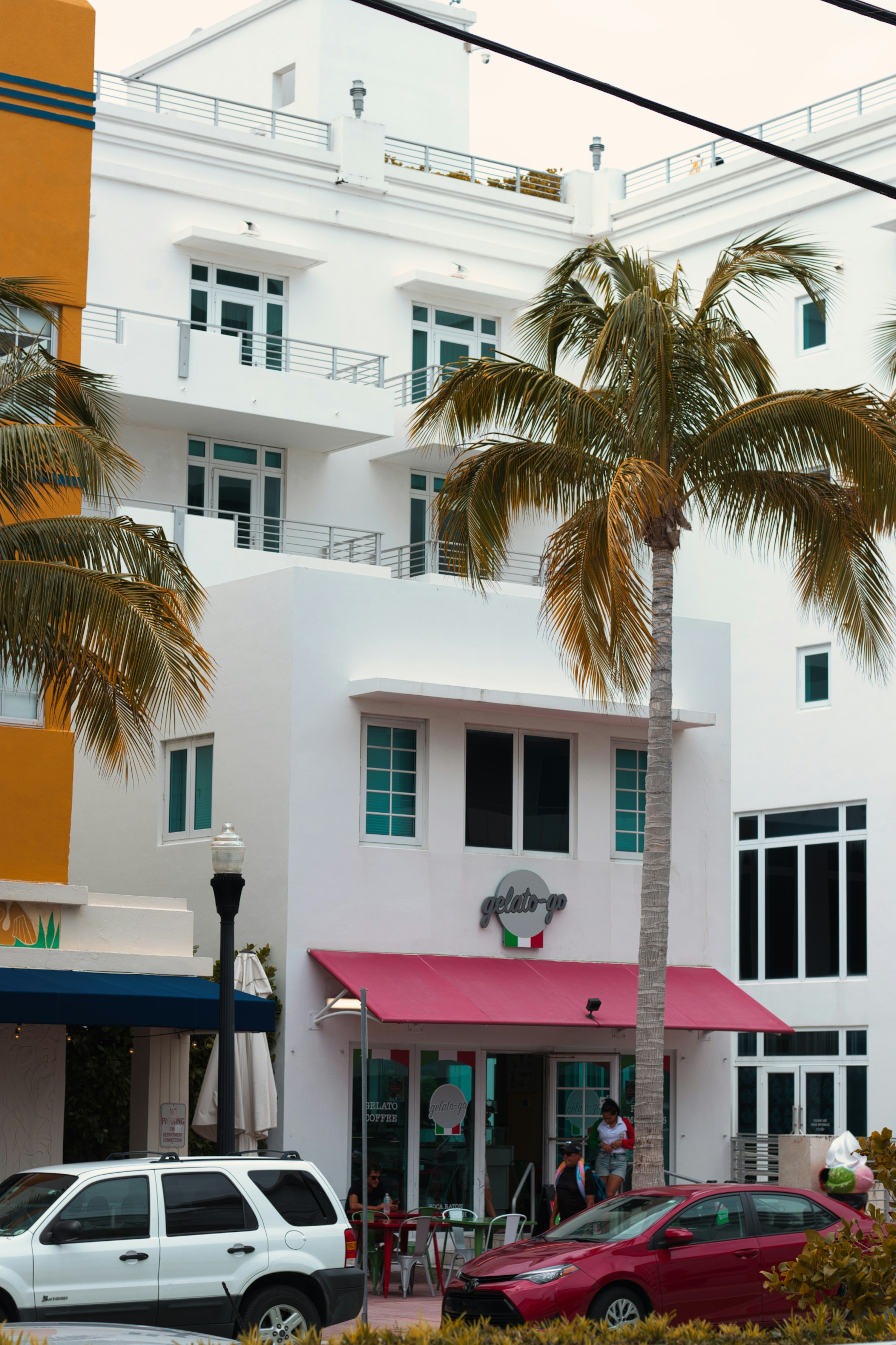 Coral Awning Café Framed by Tropical Palms on a Sunlit Street