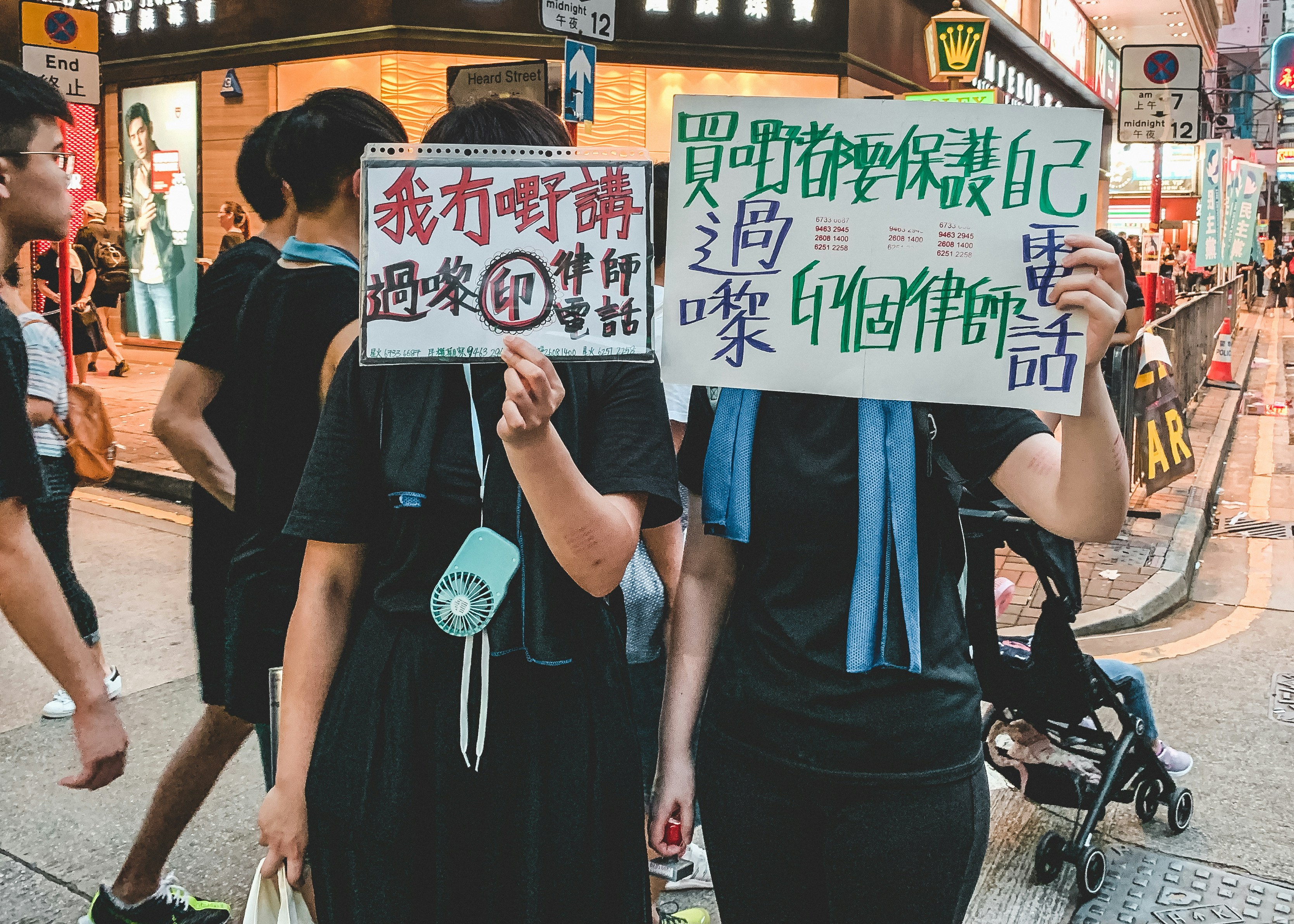 Two individuals holding signs that advocate for social issues in a bustling urban environment, highlighting the spirit of activism.