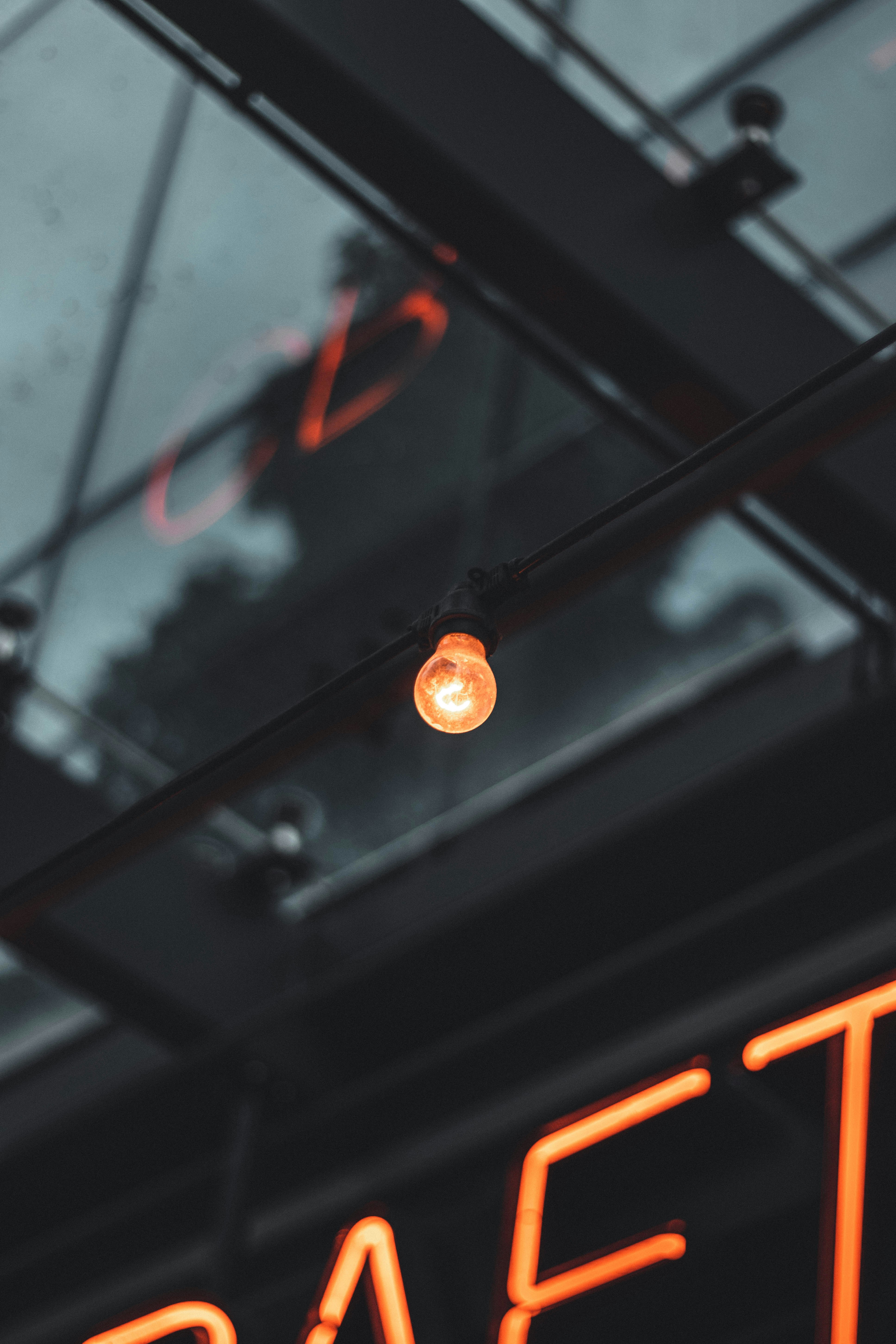 A glowing light bulb hangs against a backdrop of reflective surfaces, hinting at urban life and creativity.