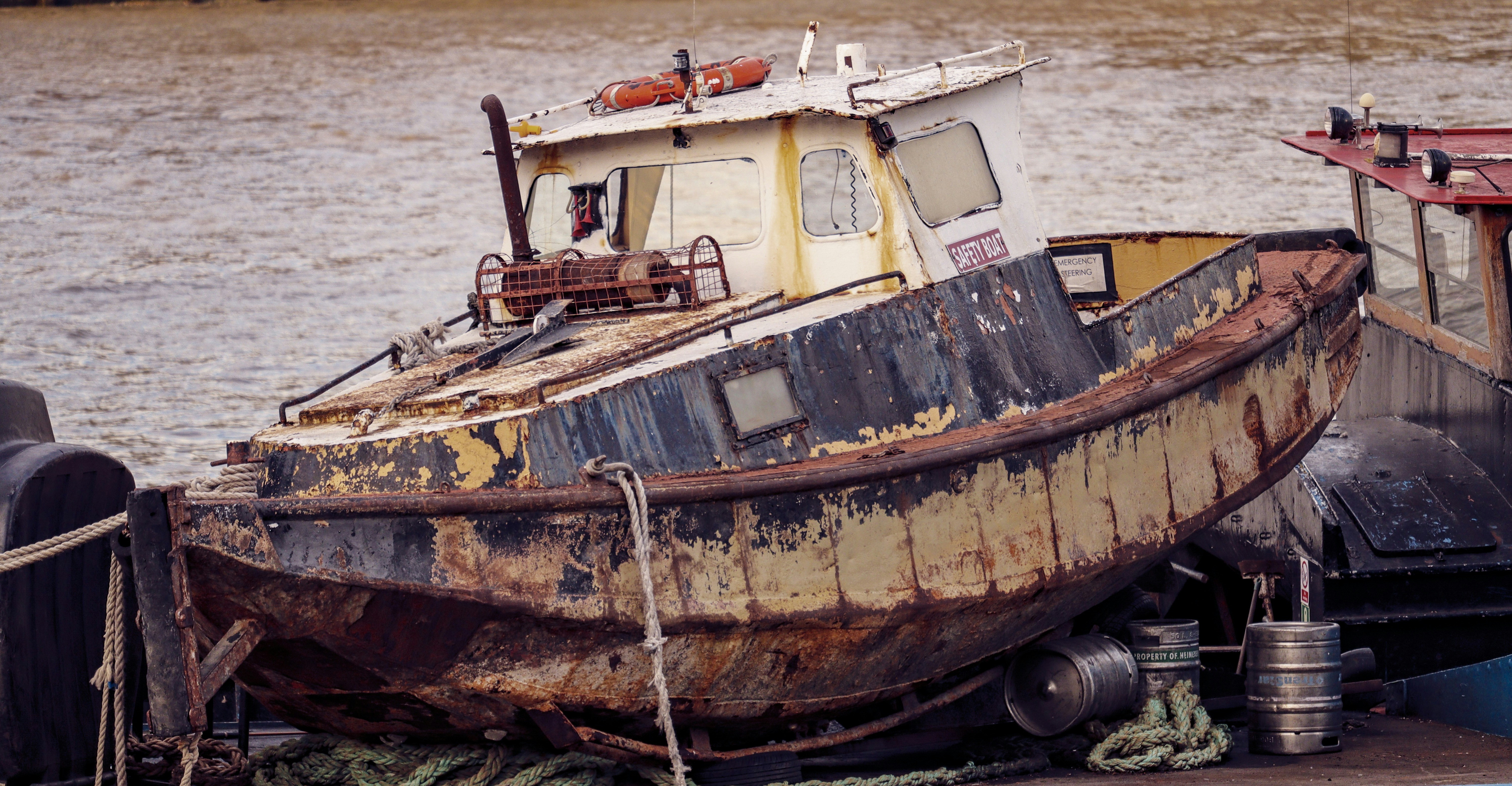 An abandoned, weathered boat rests against the dock, showcasing its peeling paint and rustic charm. The tranquil waters reflect its storied past.