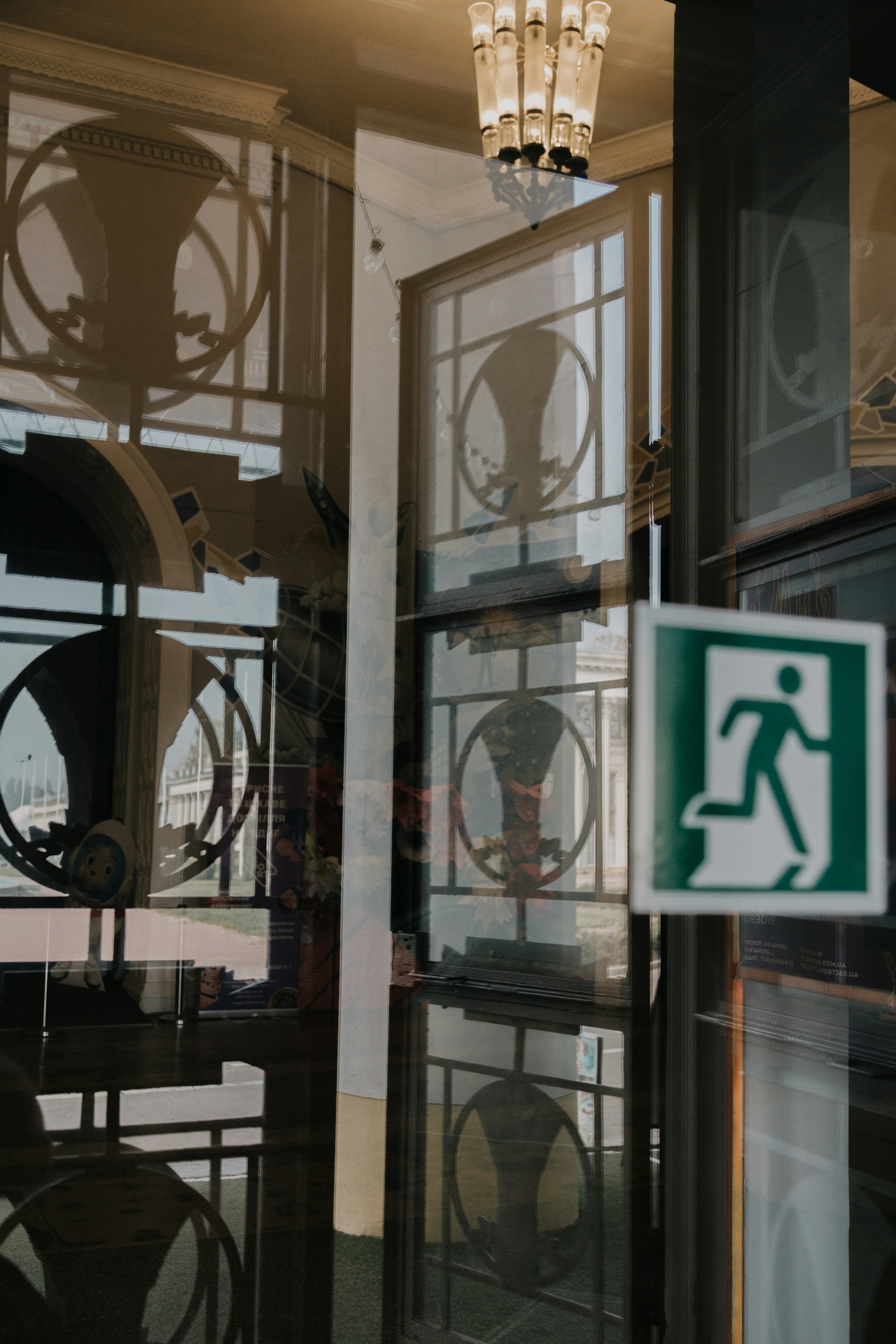 Glass Door Reflections and Emergency Sign in a Dim Interior