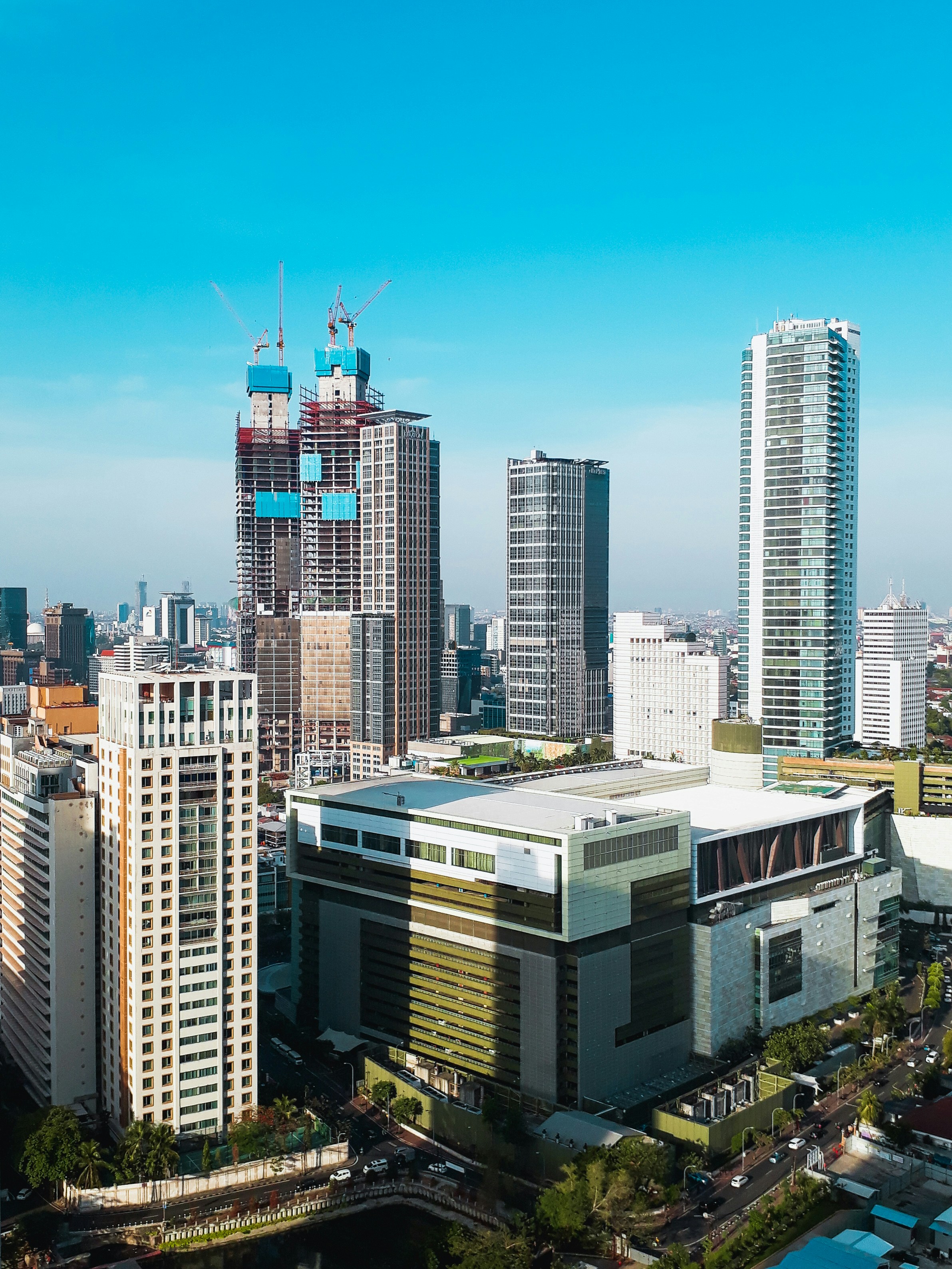 Aerial view of a bustling cityscape featuring modern skyscrapers and ongoing construction, showcasing urban development and architectural diversity.