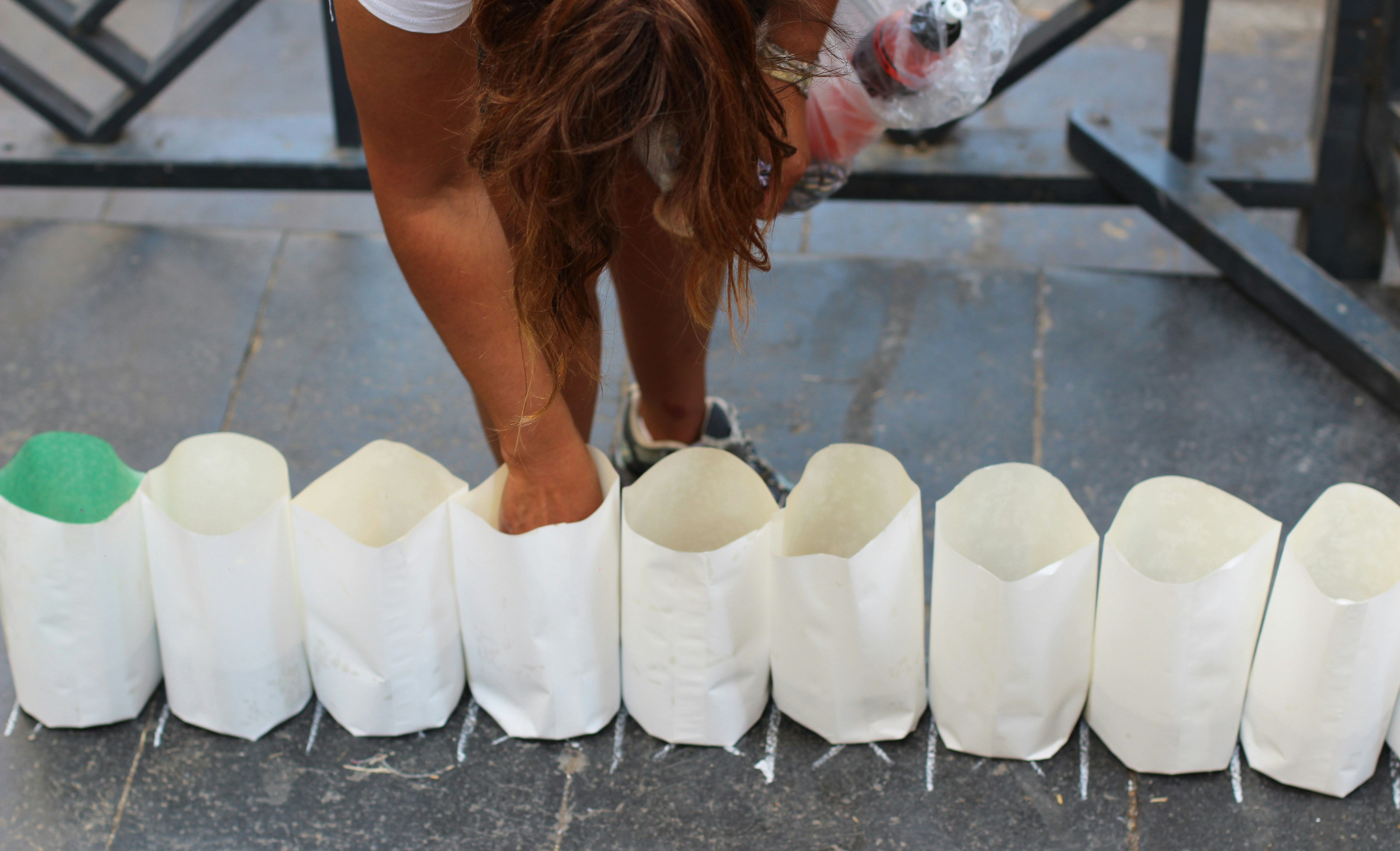 A person engages in a creative task involving white paper containers, showcasing a unique artistic process. The focus is on the hands and the carefully arranged containers.