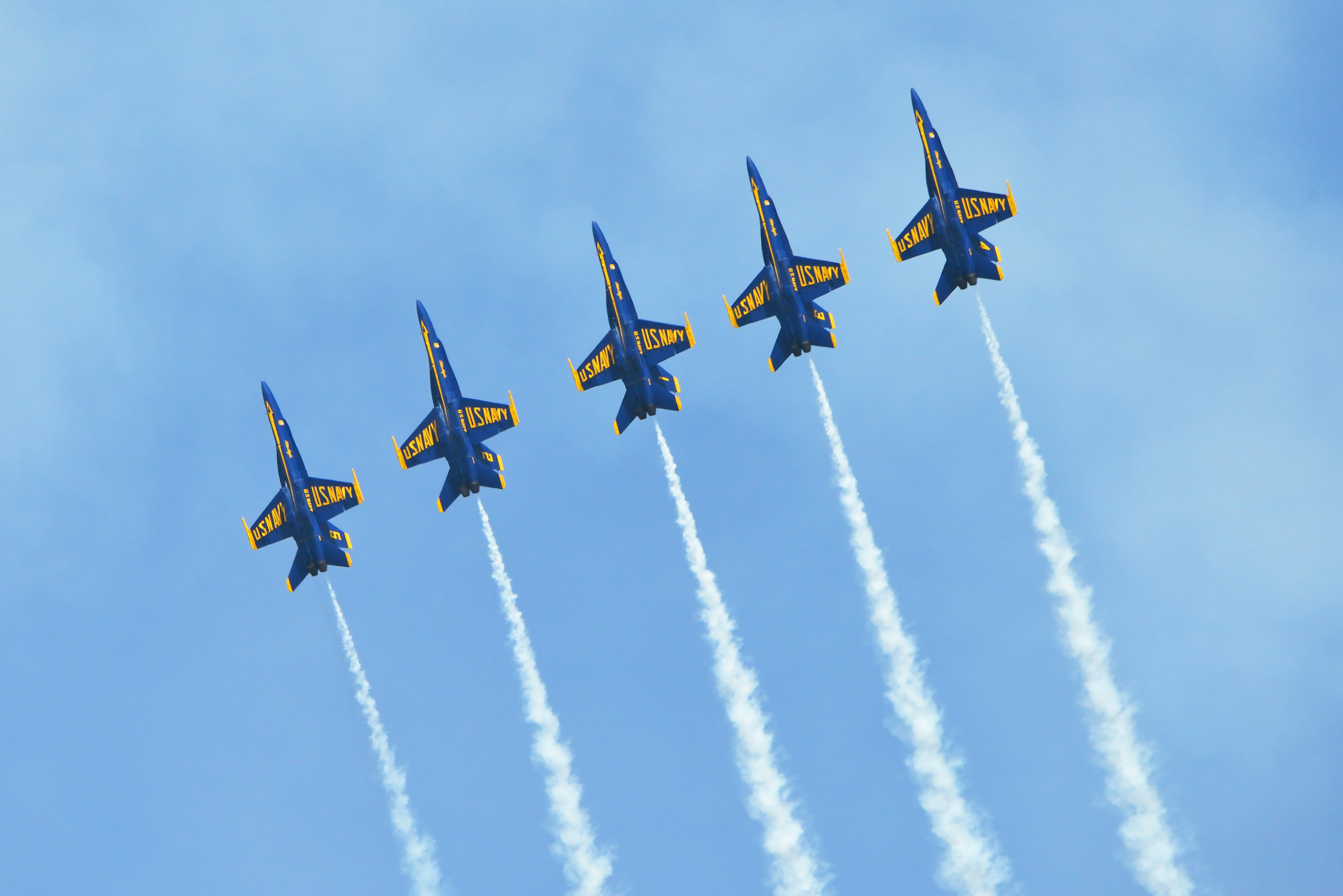 Cinco aviones azules y amarillos volando con estelas de condensación ...
