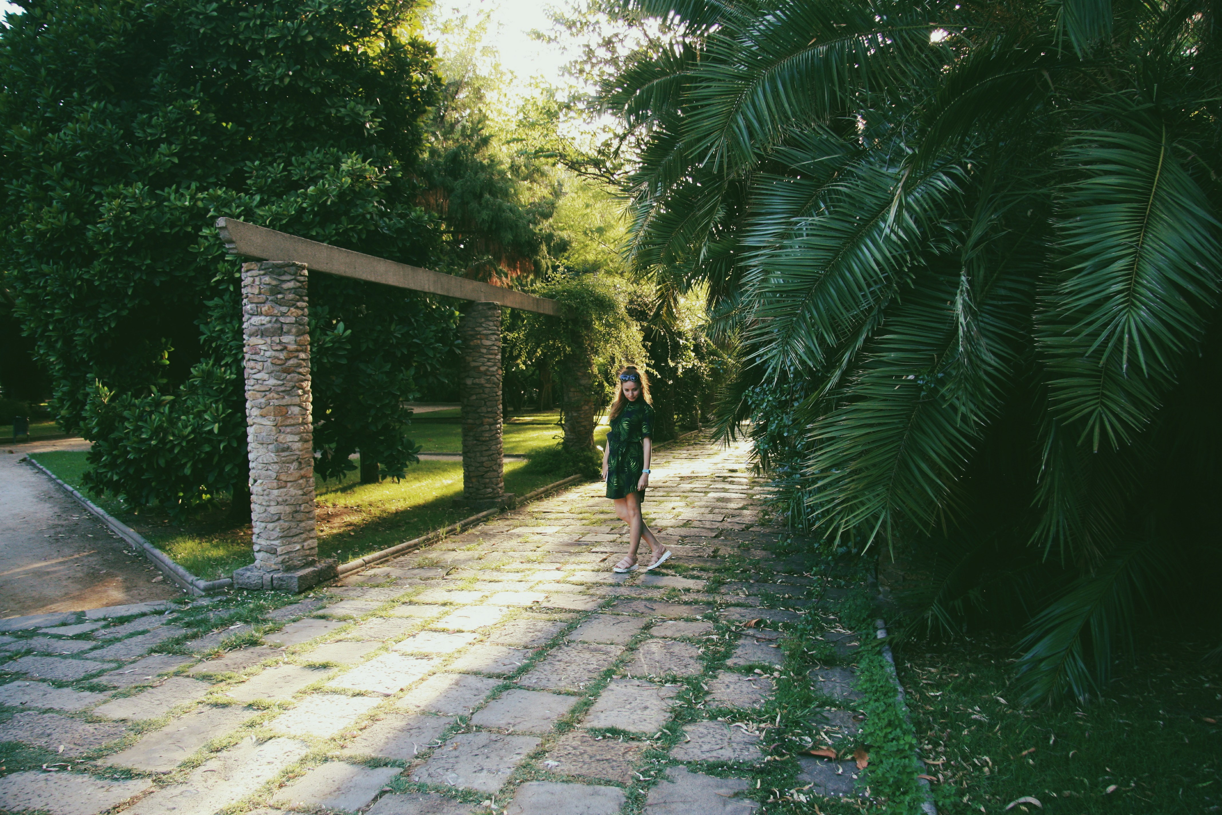 Girl in a green dress among palm trees in the garden