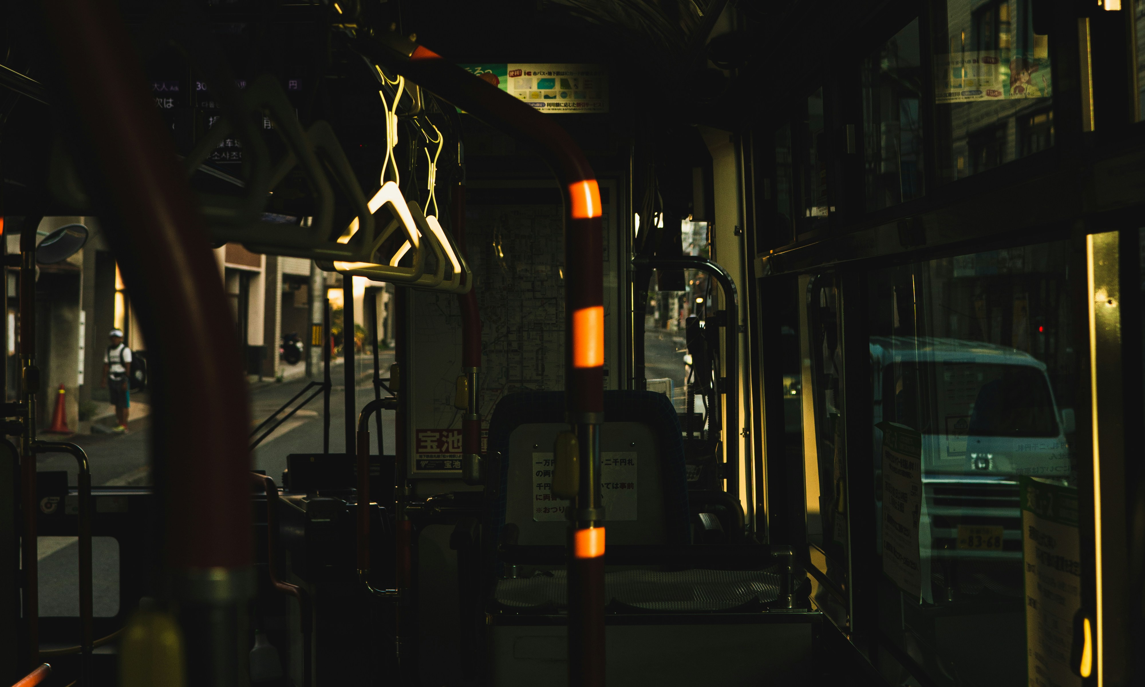 Interior view of a city bus with warm light illuminating the handrails and seats, showcasing the quiet moments of urban travel.