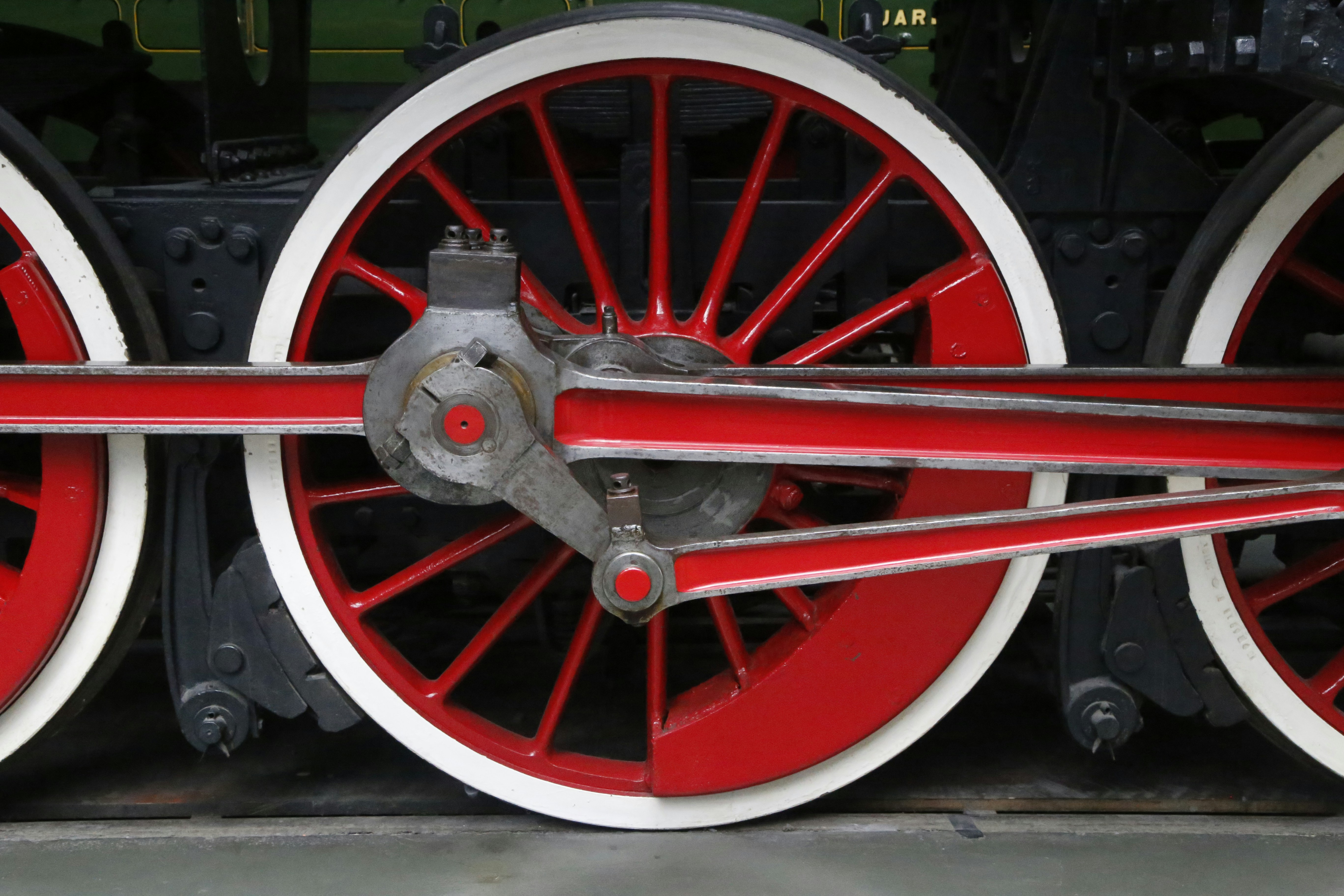Close-up of a steam locomotive's red and white wheels with detailed mechanical components.