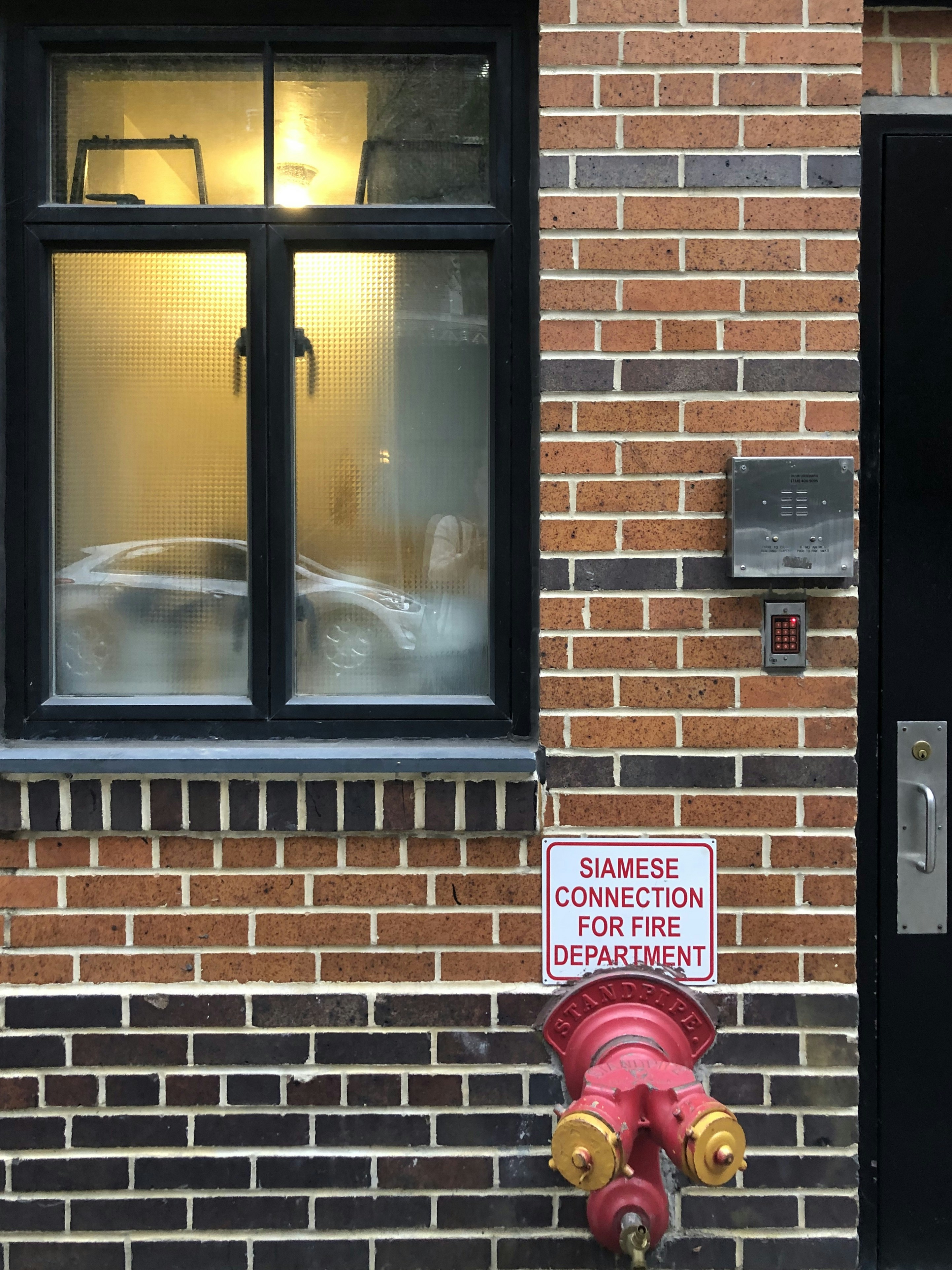 Brick Facade Portrait: The Red Hydrant Anchors a Quiet Urban Window Scene