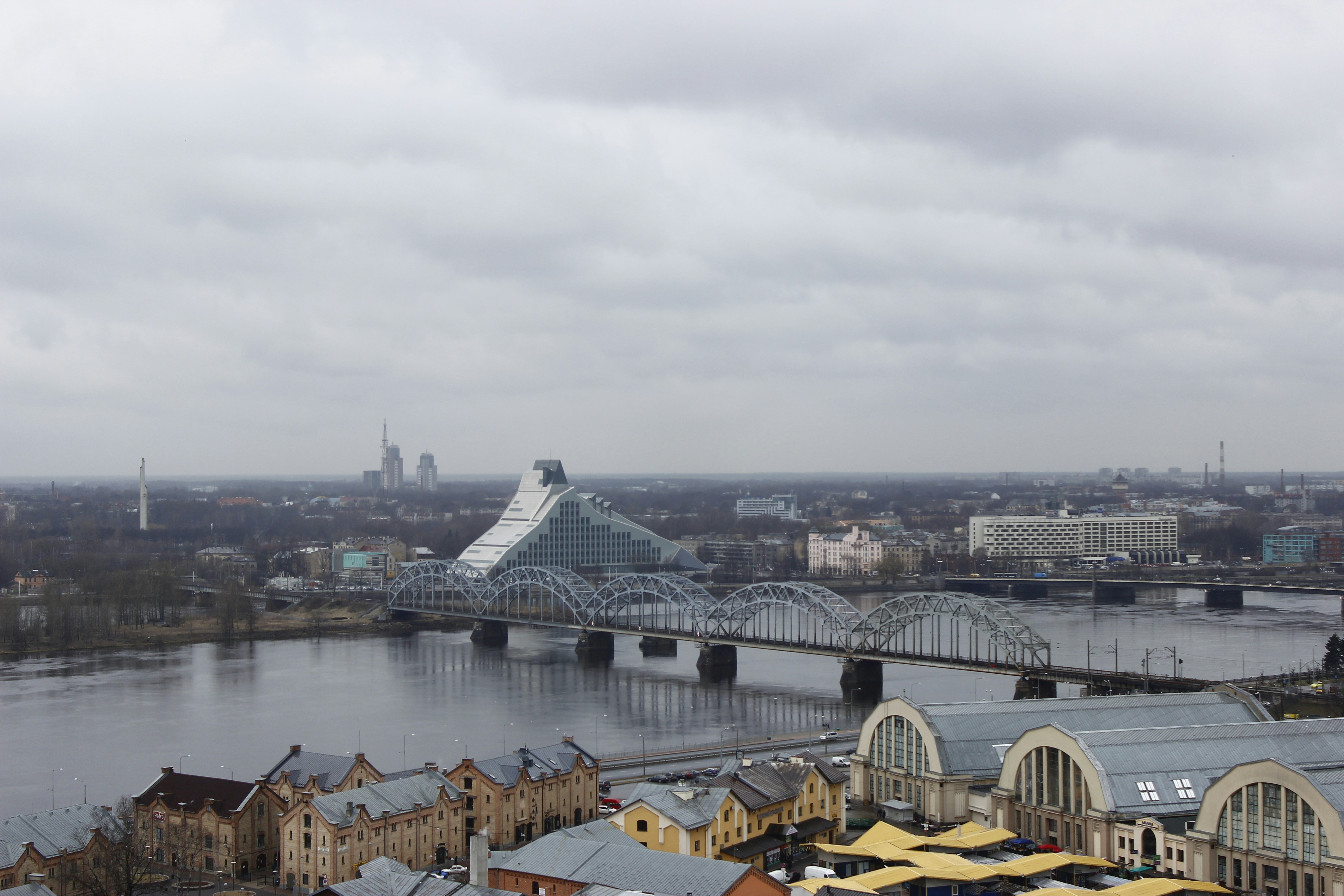 Aerial view of Riga showcasing the river, bridges, and distinct architecture against a cloudy winter backdrop.