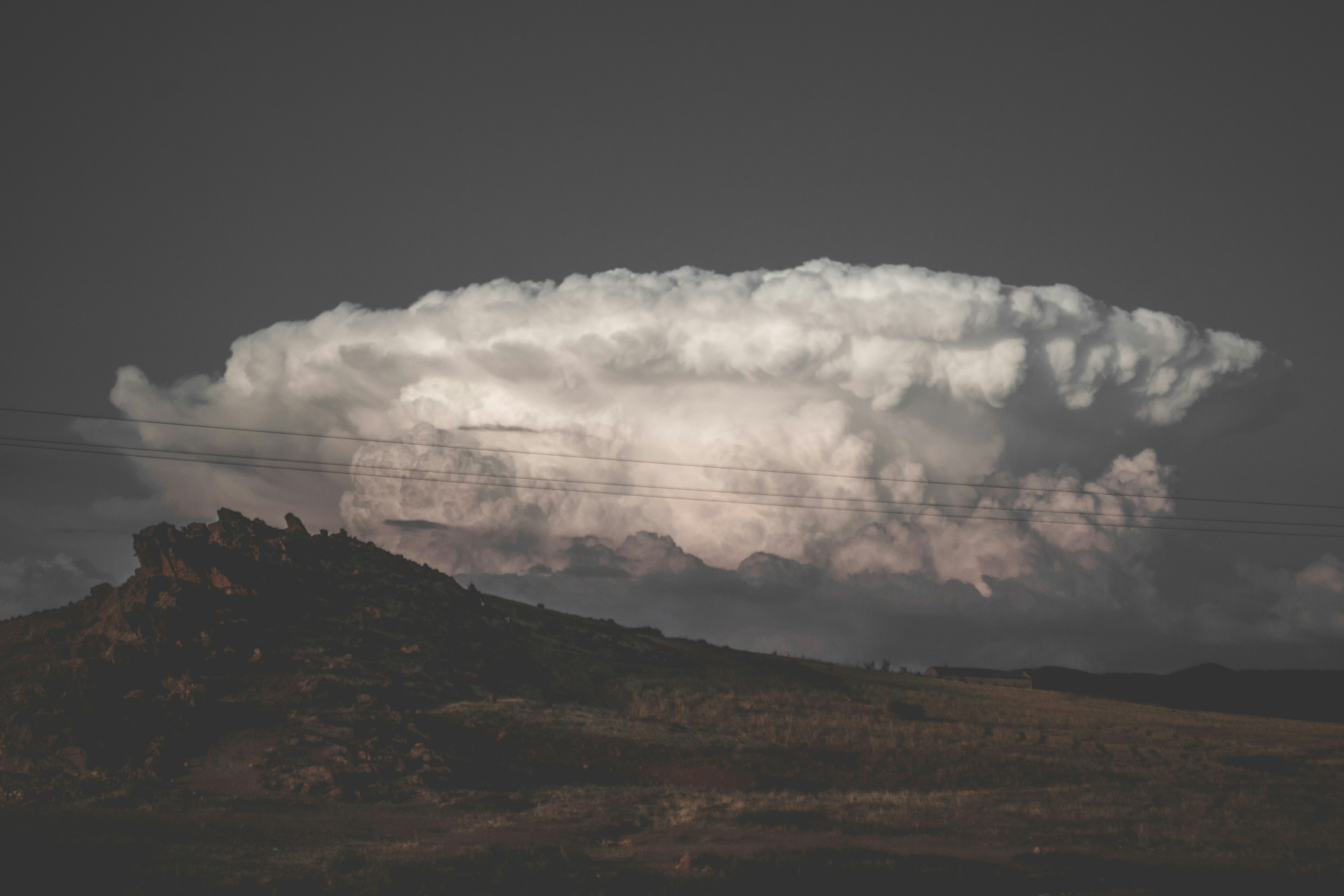 Colossal Cloud Looms Over Desert Ridge at Dusk