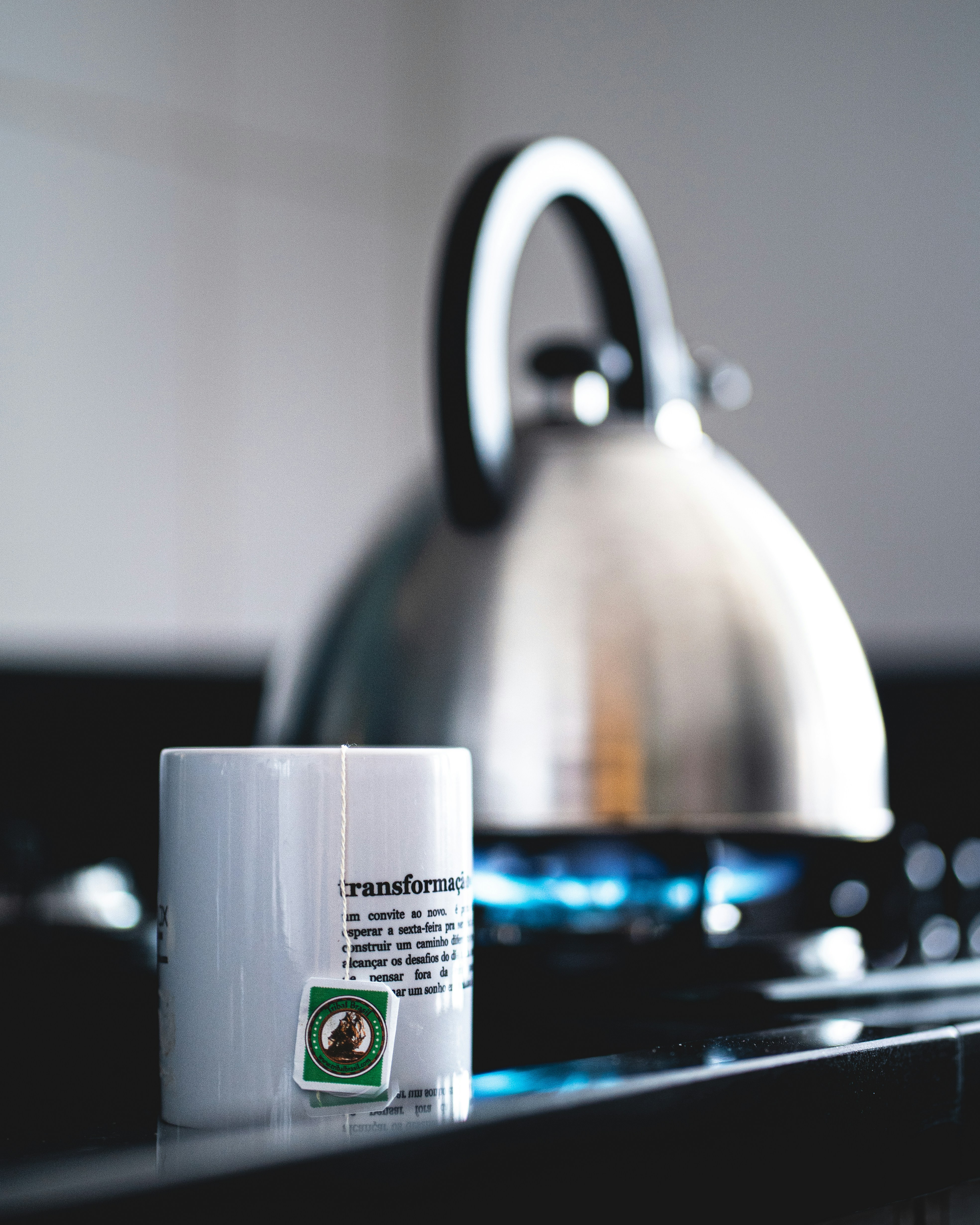 Shallow Focus in a Quiet Kitchen: A White Ceramic Cup with a Green Label on a Glossy Stove