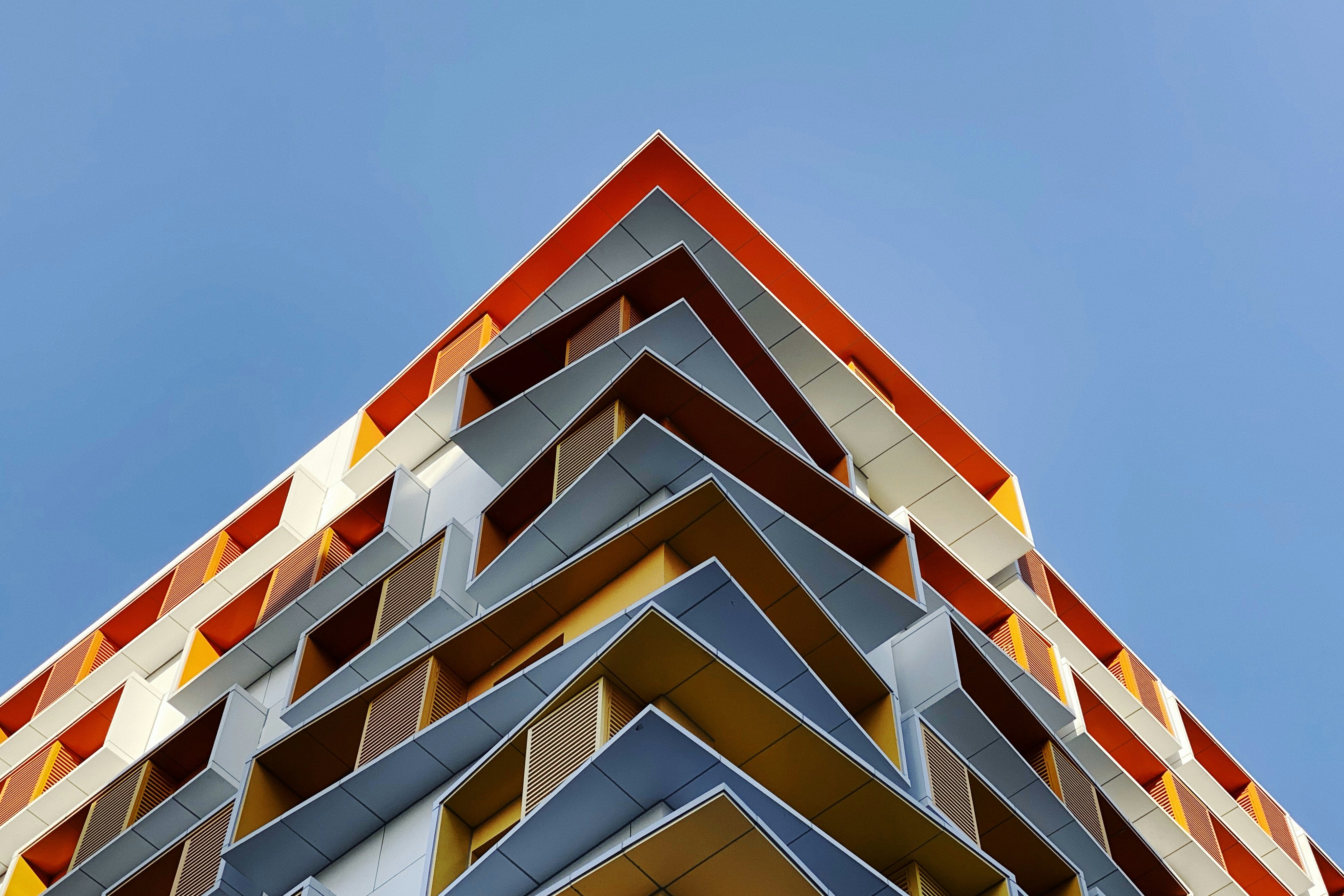 Colorful building facade viewed from below against a clear blue sky.