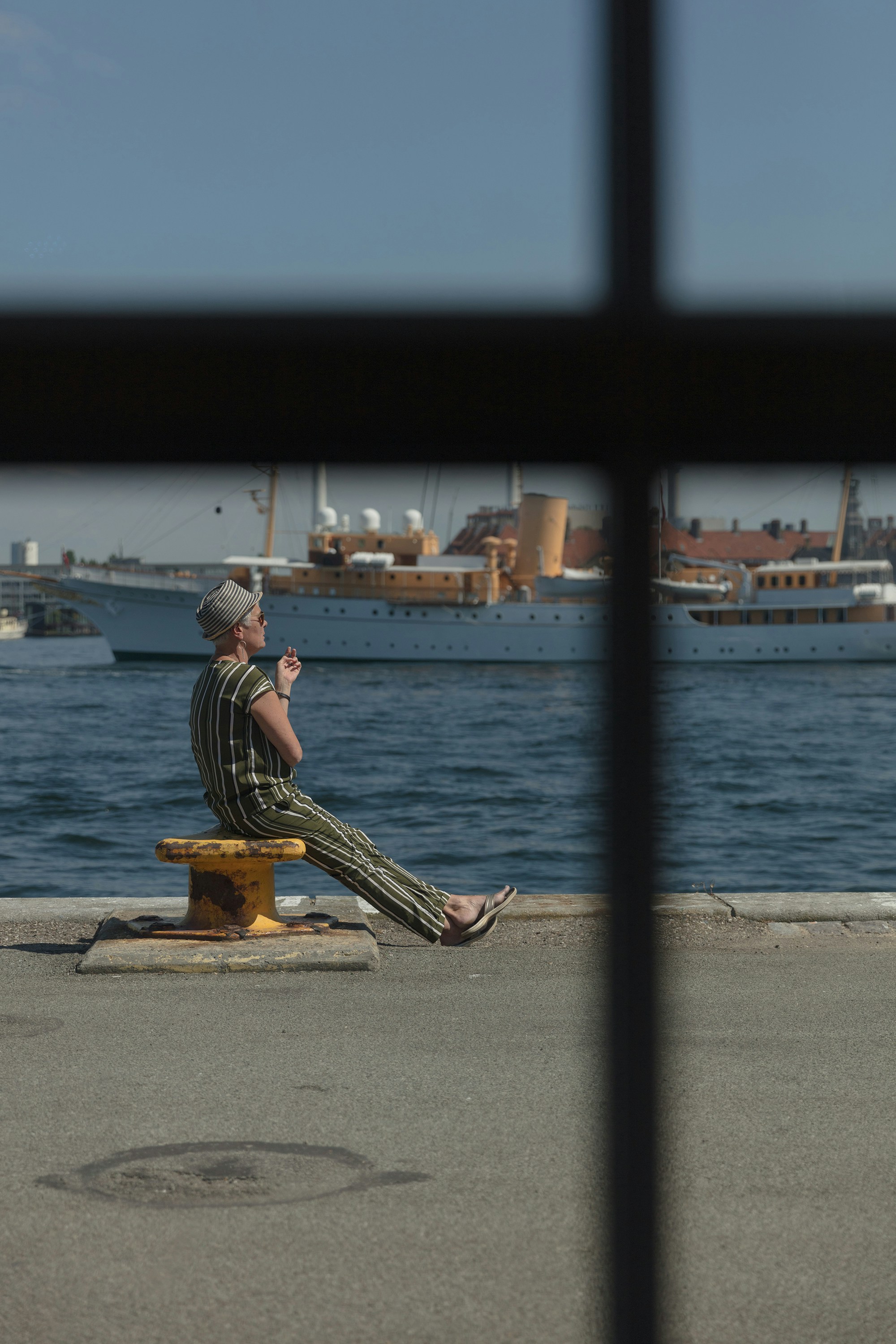 Harbor Grids: Striped Figure on a Bollard with a Ship Looming in the Distance