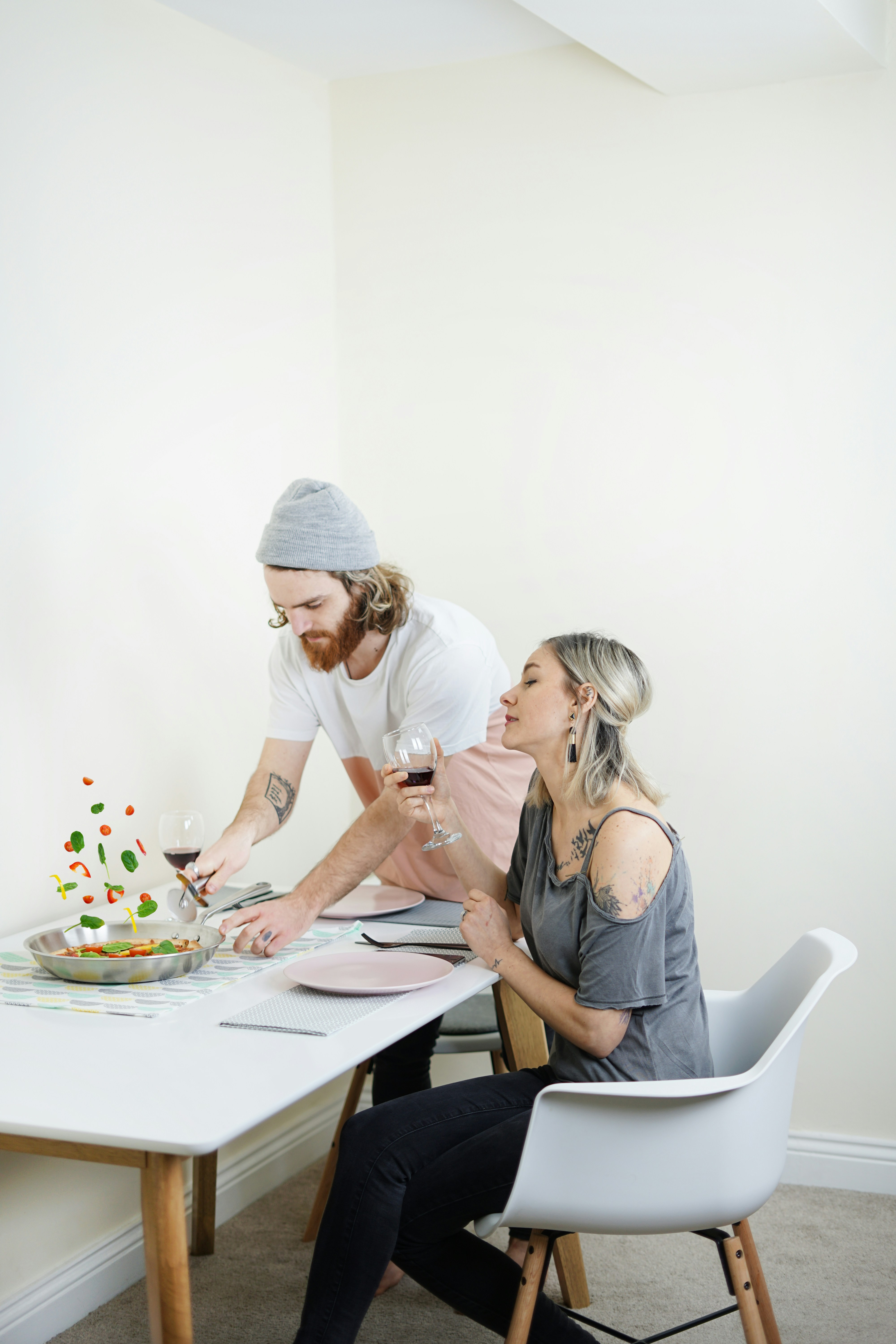White-Walled Dinner: A Beanie-Clad Moment of Wine and Colorful Plates