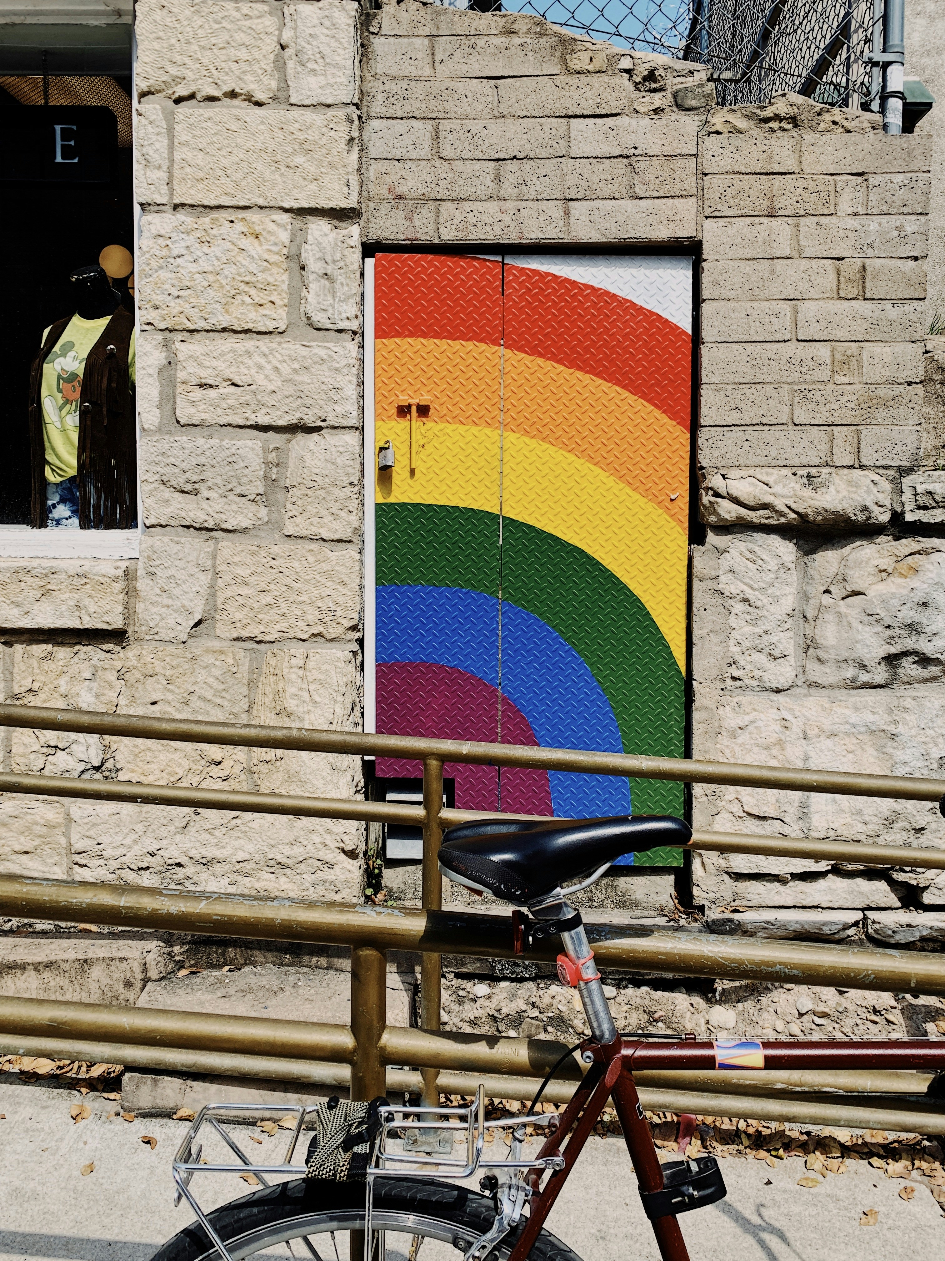 Rainbow Threshold: A Vibrant Door Framed by Stone and Rails