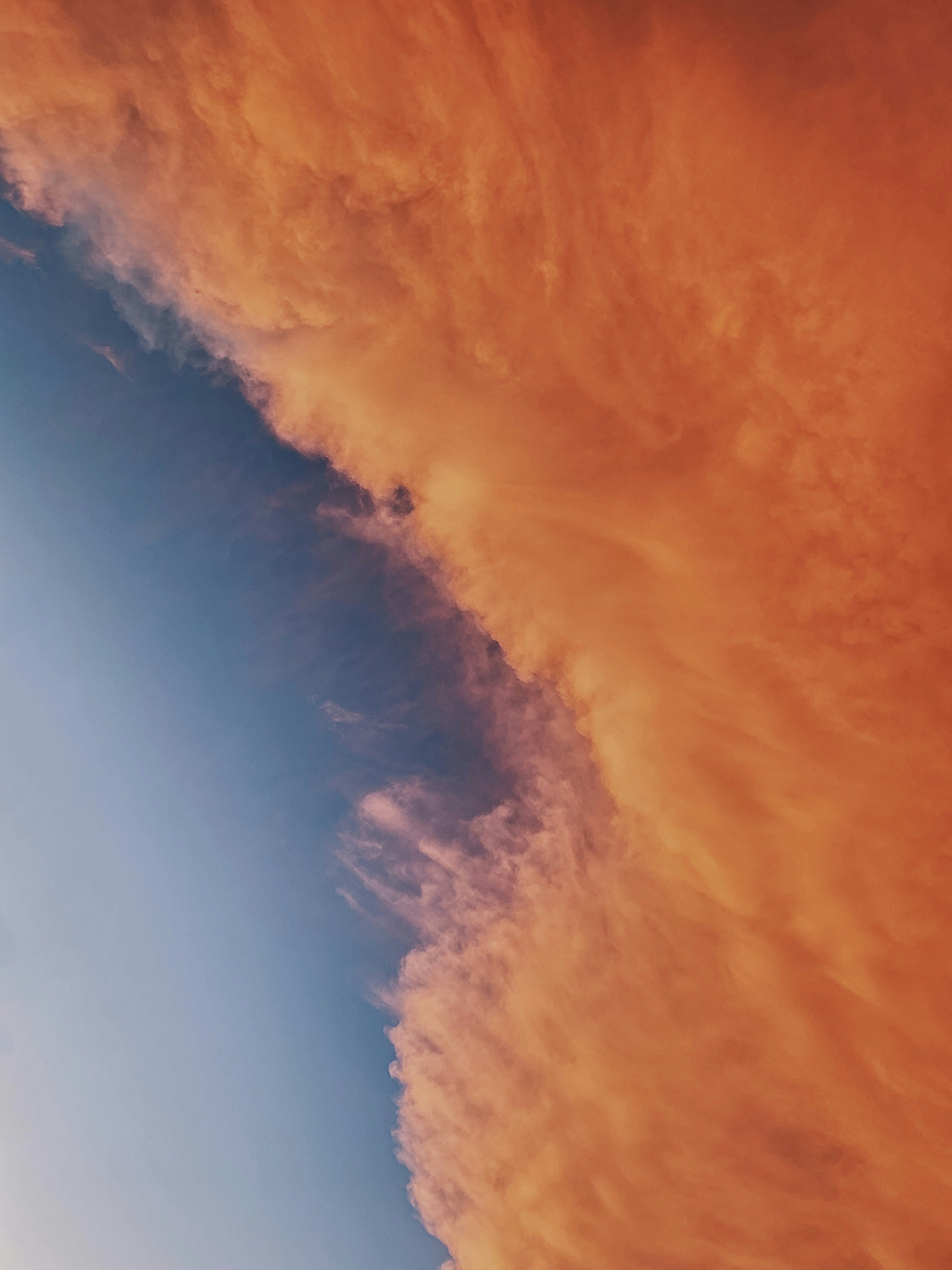 Vibrant cloud formations transition from deep orange to serene blue, illustrating the meeting of day and night.