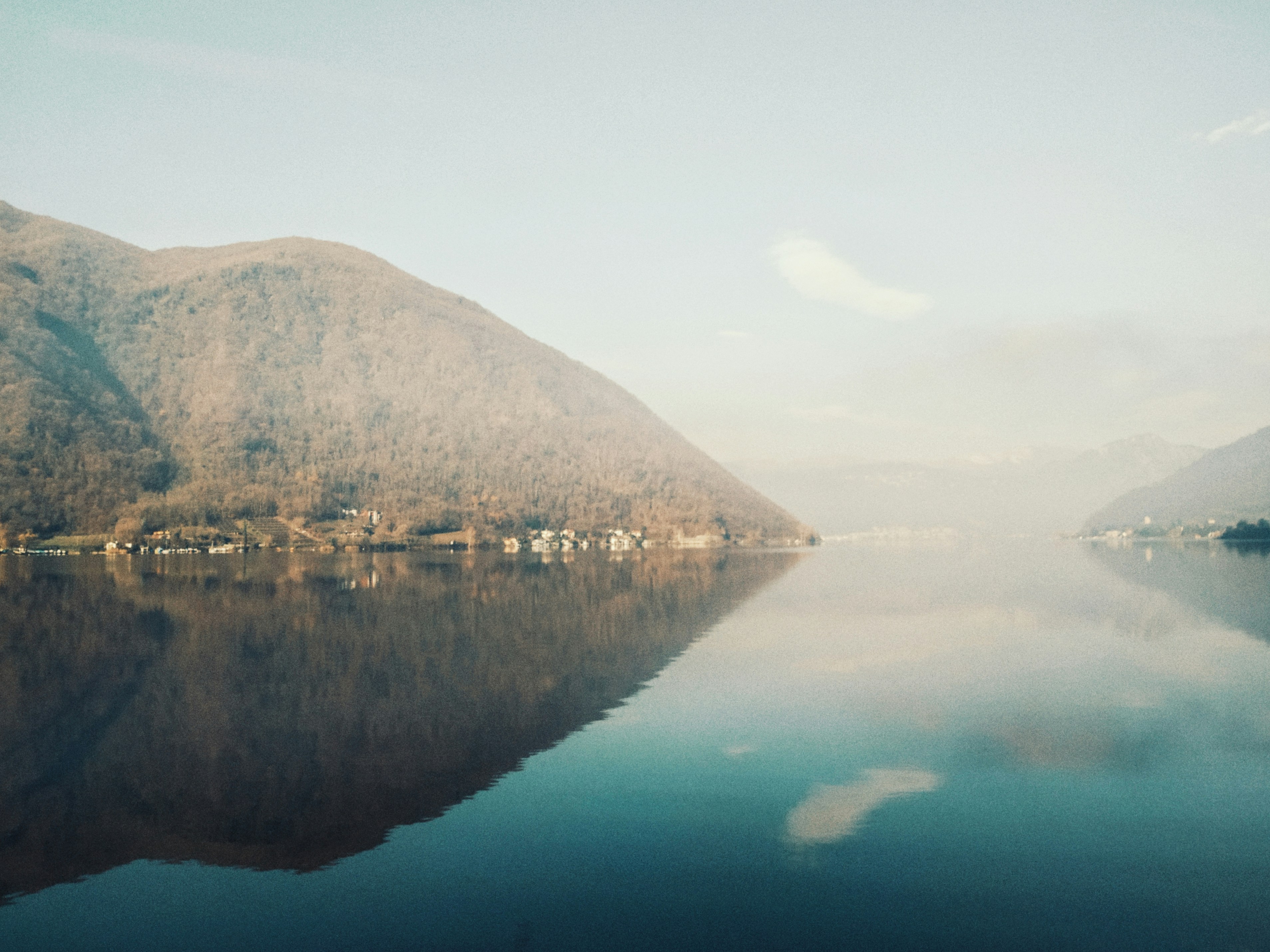 Reflection on the lake | houses near body of water viewing mountain under white and blue sky during daytime