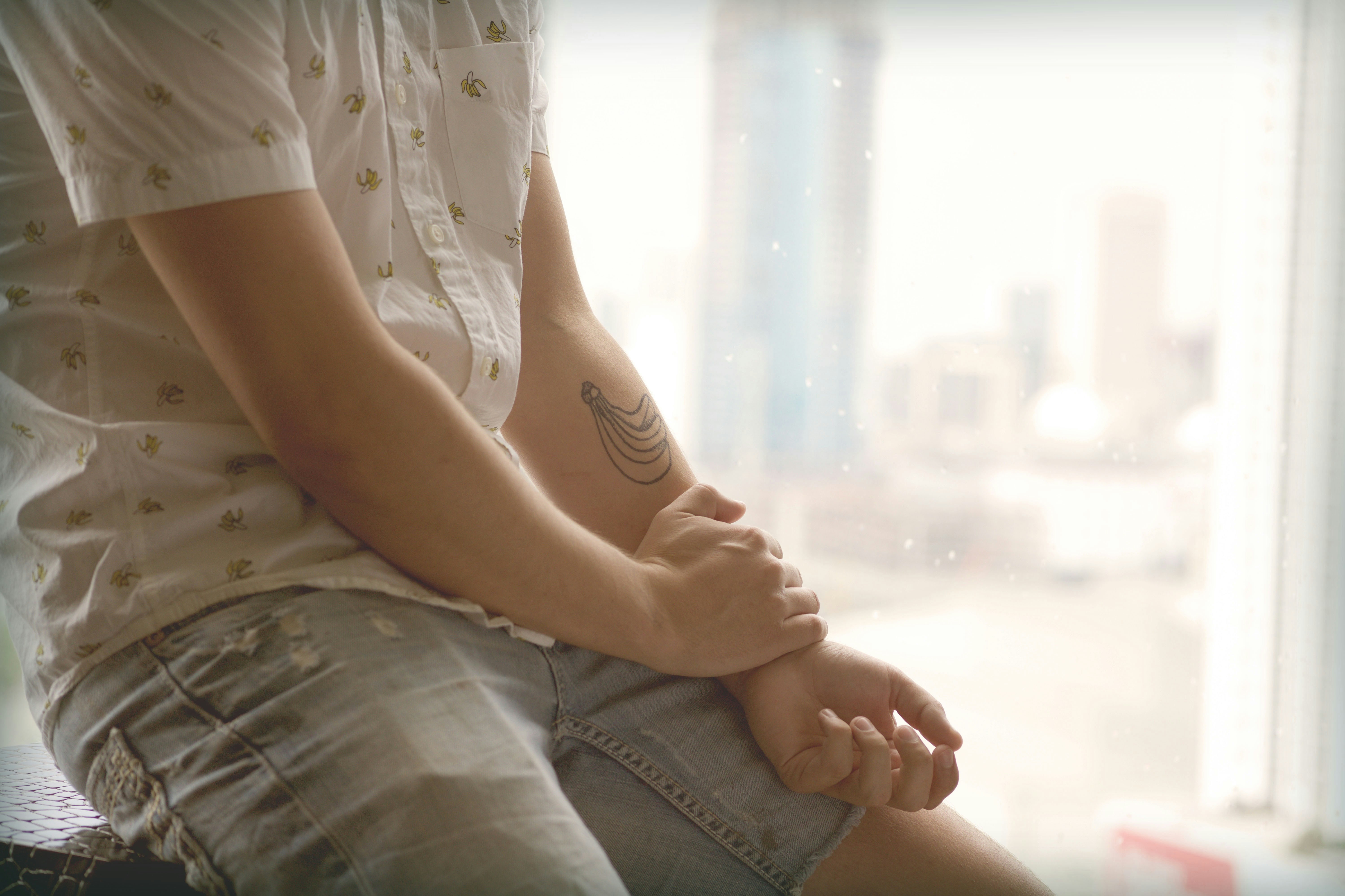 A man sitting on a window sill with his hands on his knees photo – Free ...