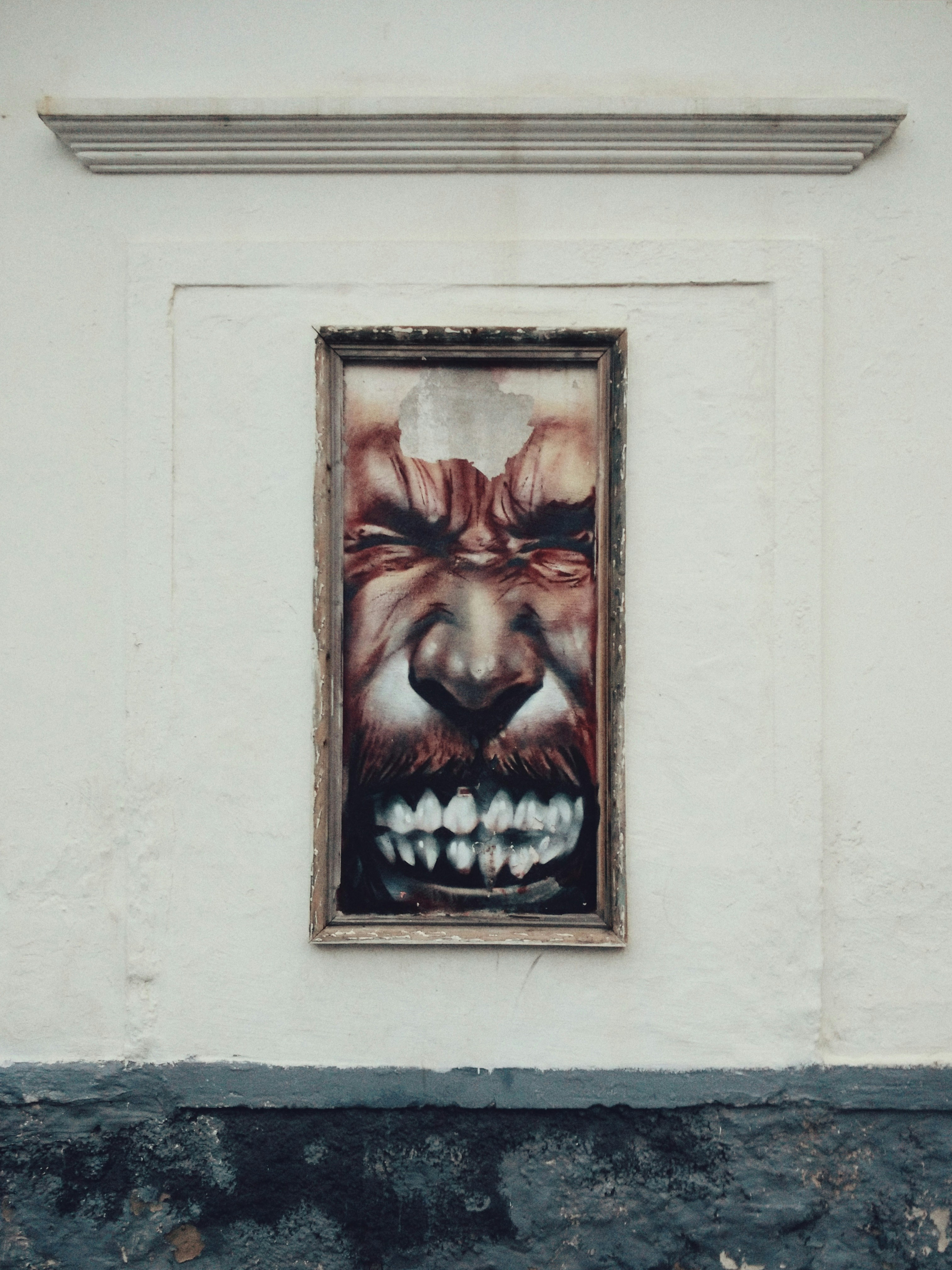 Face on the wall (mobile) | man showing teeth portrait