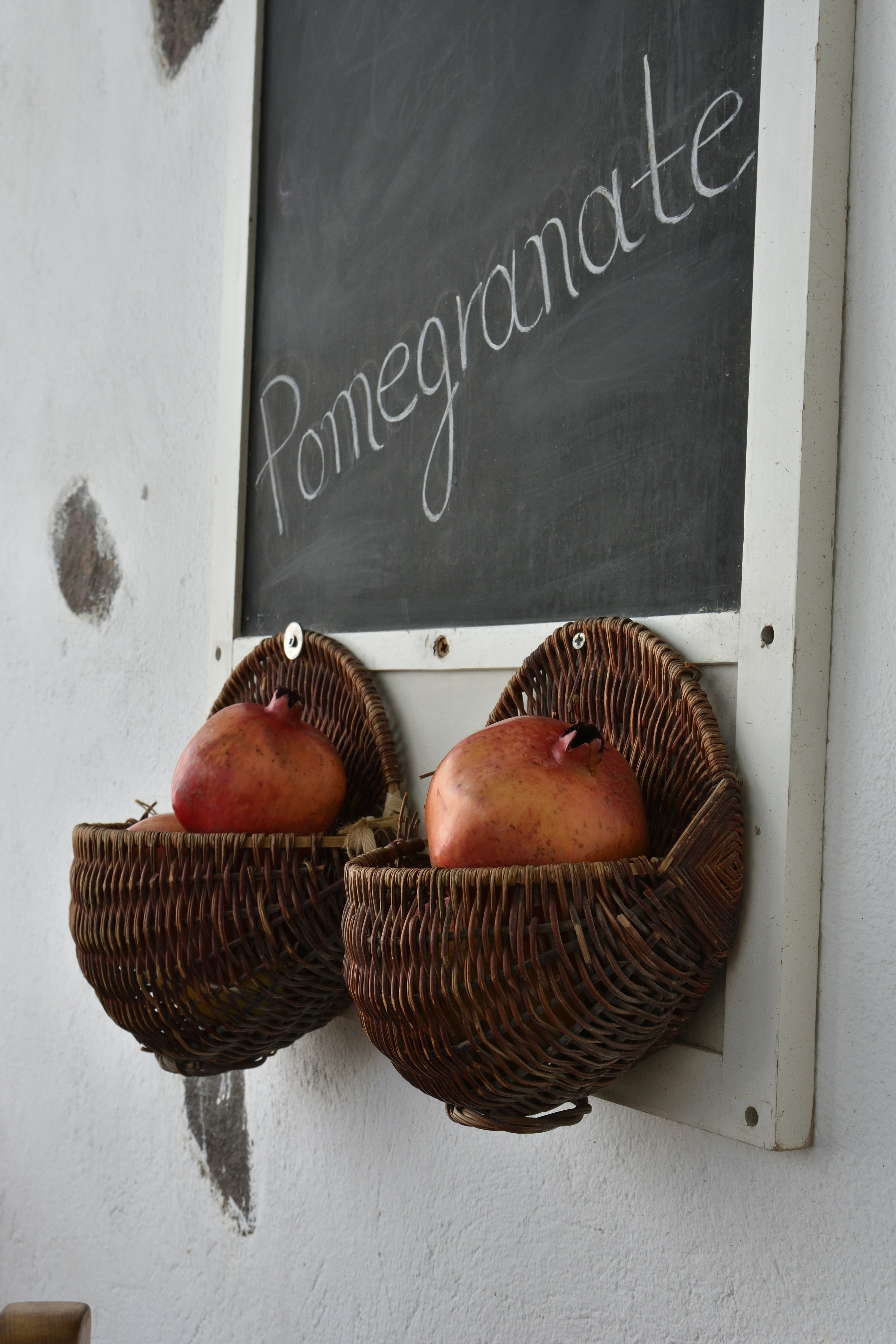 Pomegranate Duo Under a Chalkboard Sign on a White Wall