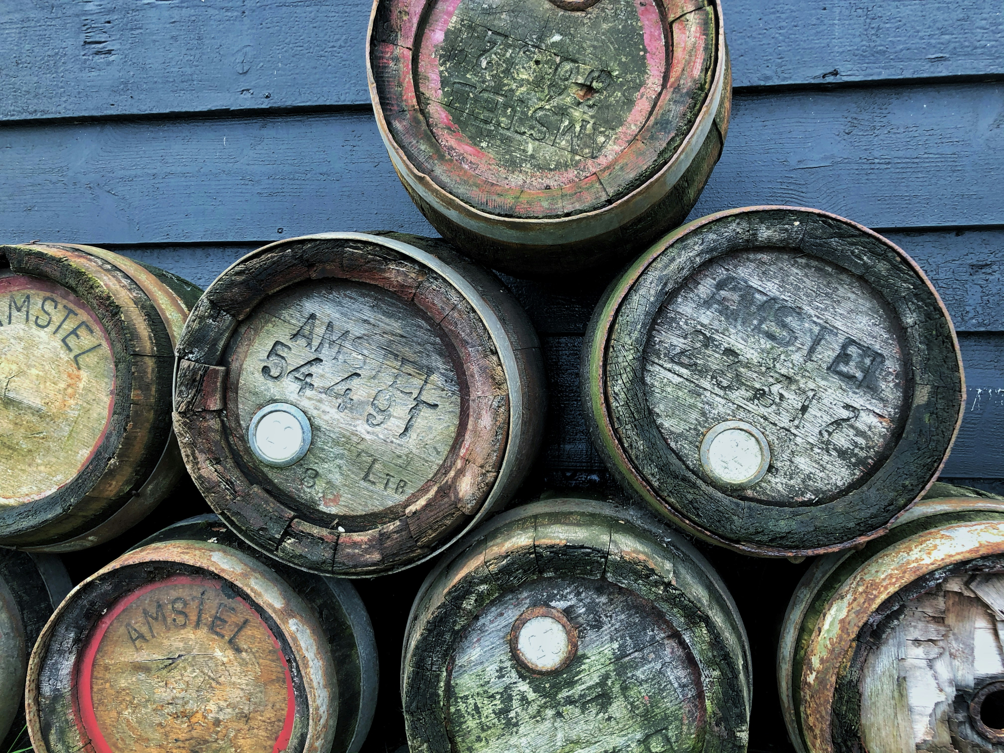 Timeworn Amstel Barrels Against Weathered Blue Siding