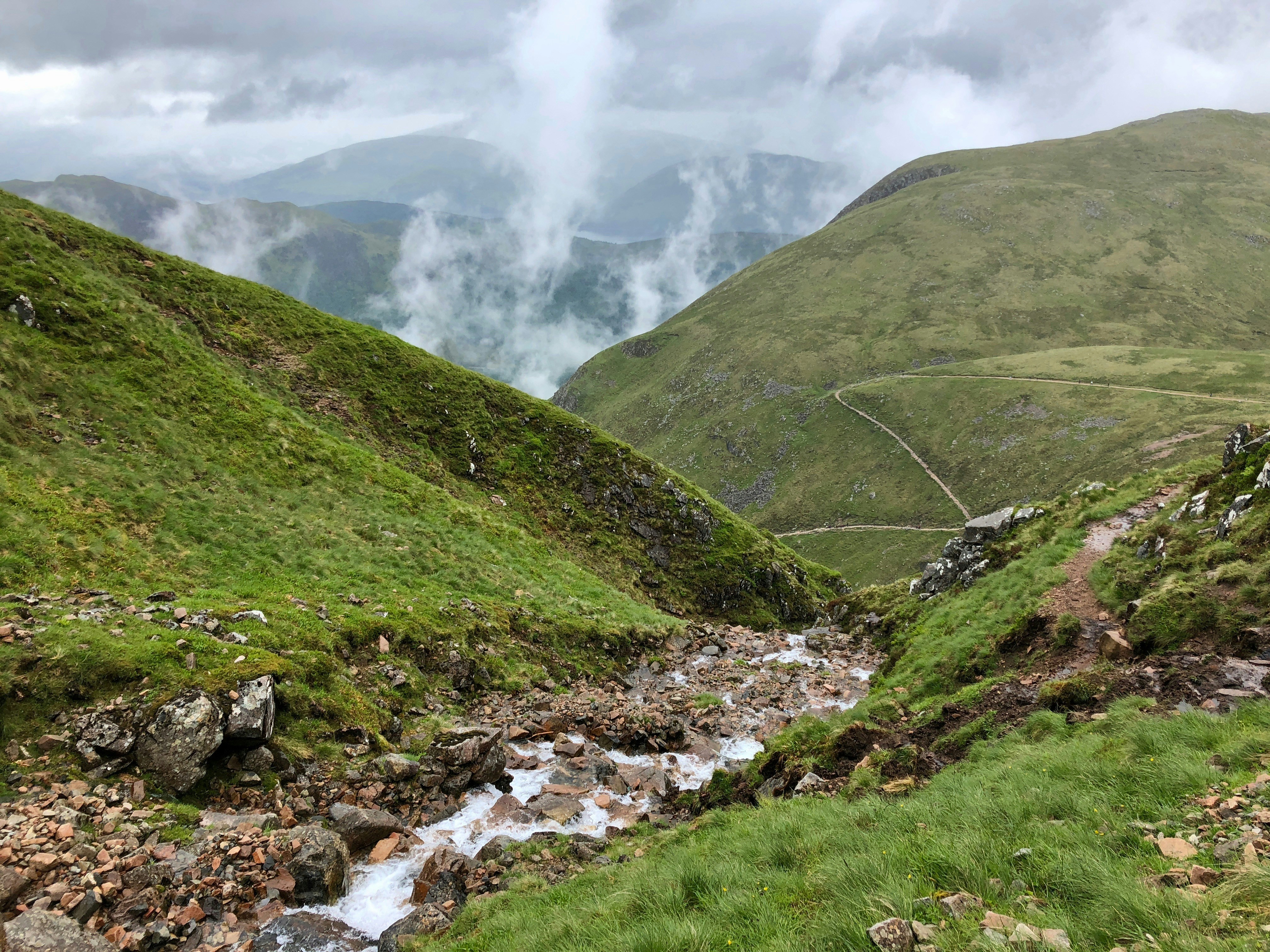 Ridge Stream: Mossy Slopes Guiding a Rocky Torrent Toward Clouded Valleys