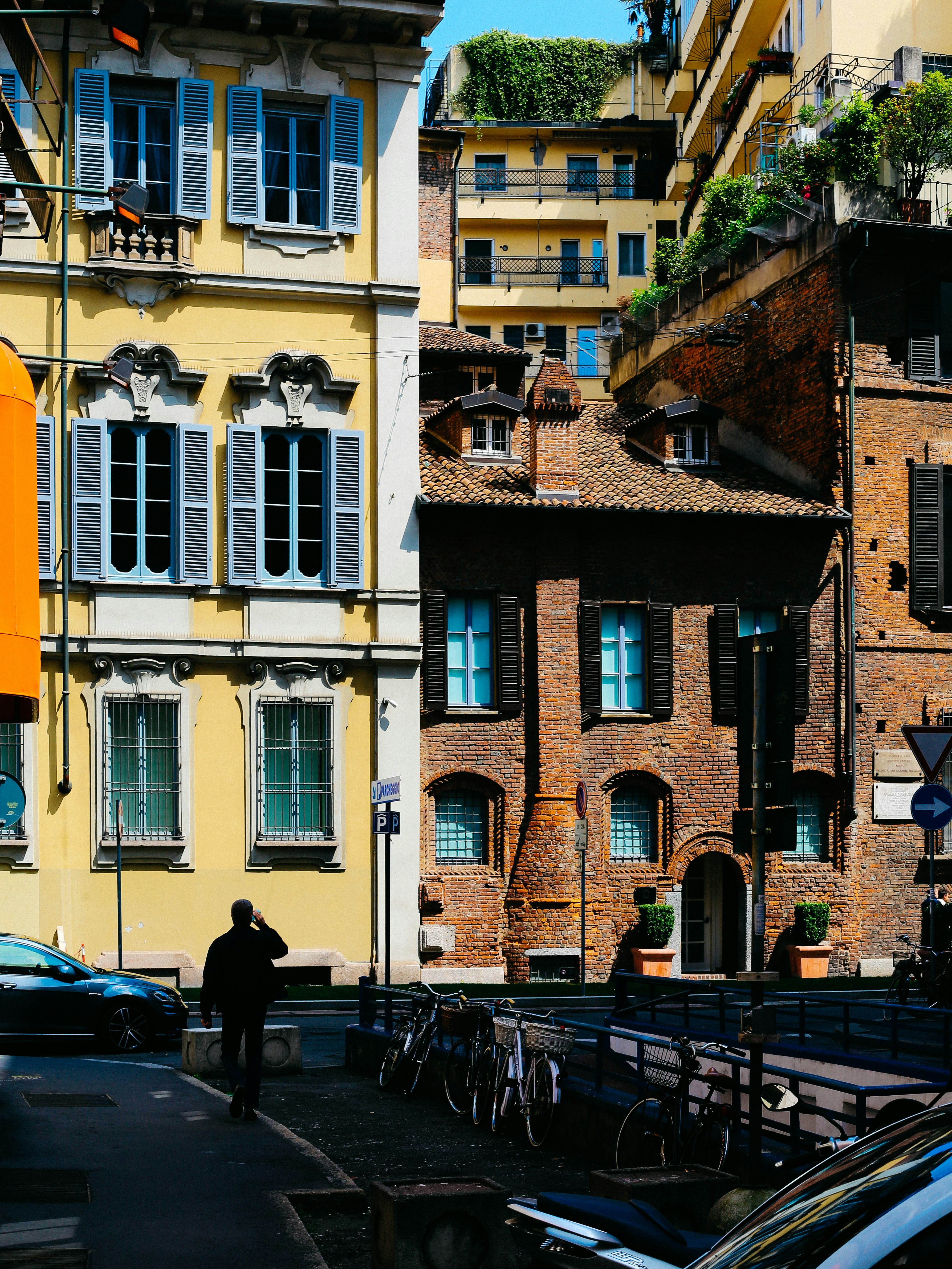 Silhouette in the Sunlit Alley Between Yellow and Brick Facades