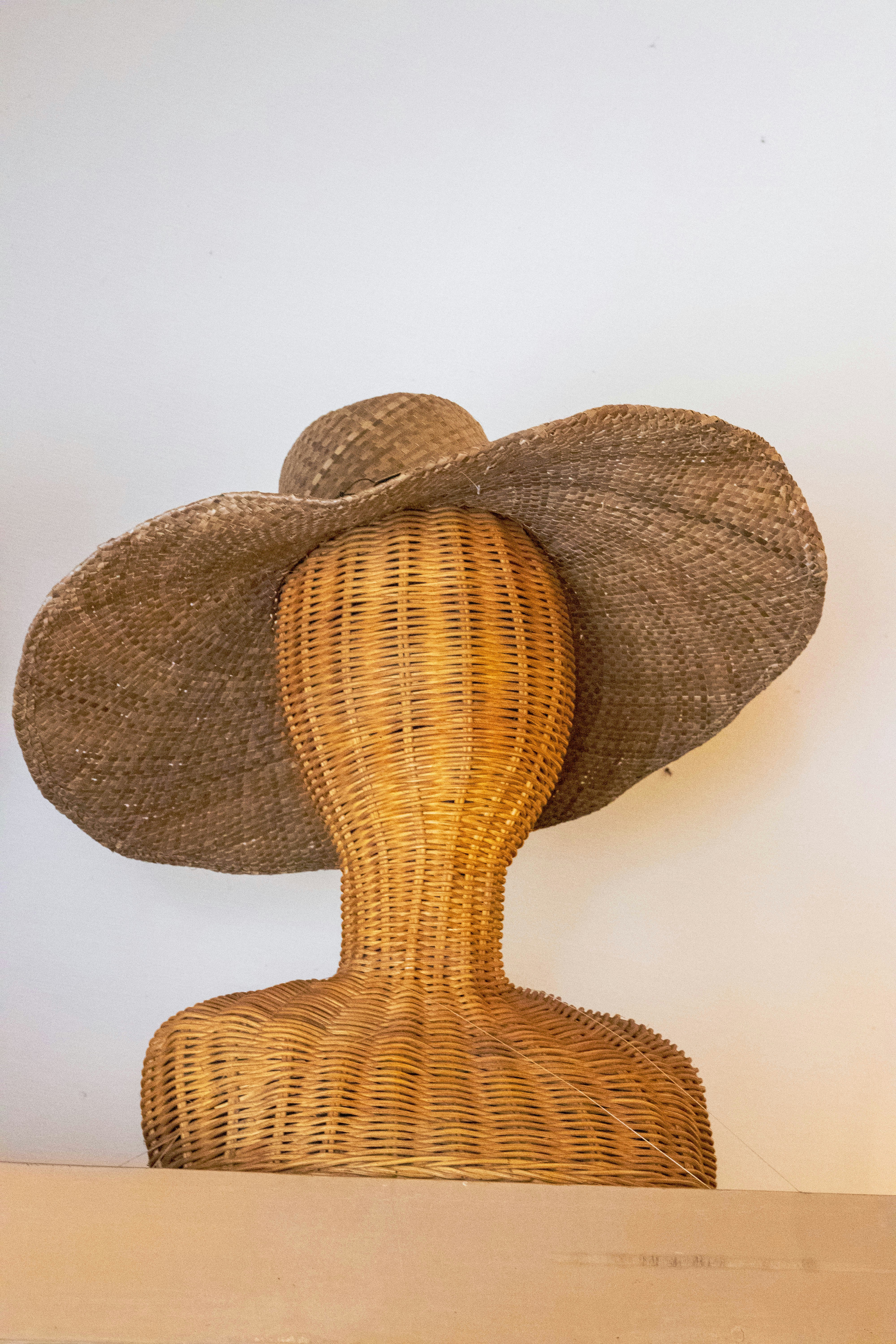 a wicker hat display on a fashion store | brown strawhat on brown wicker mannequin
