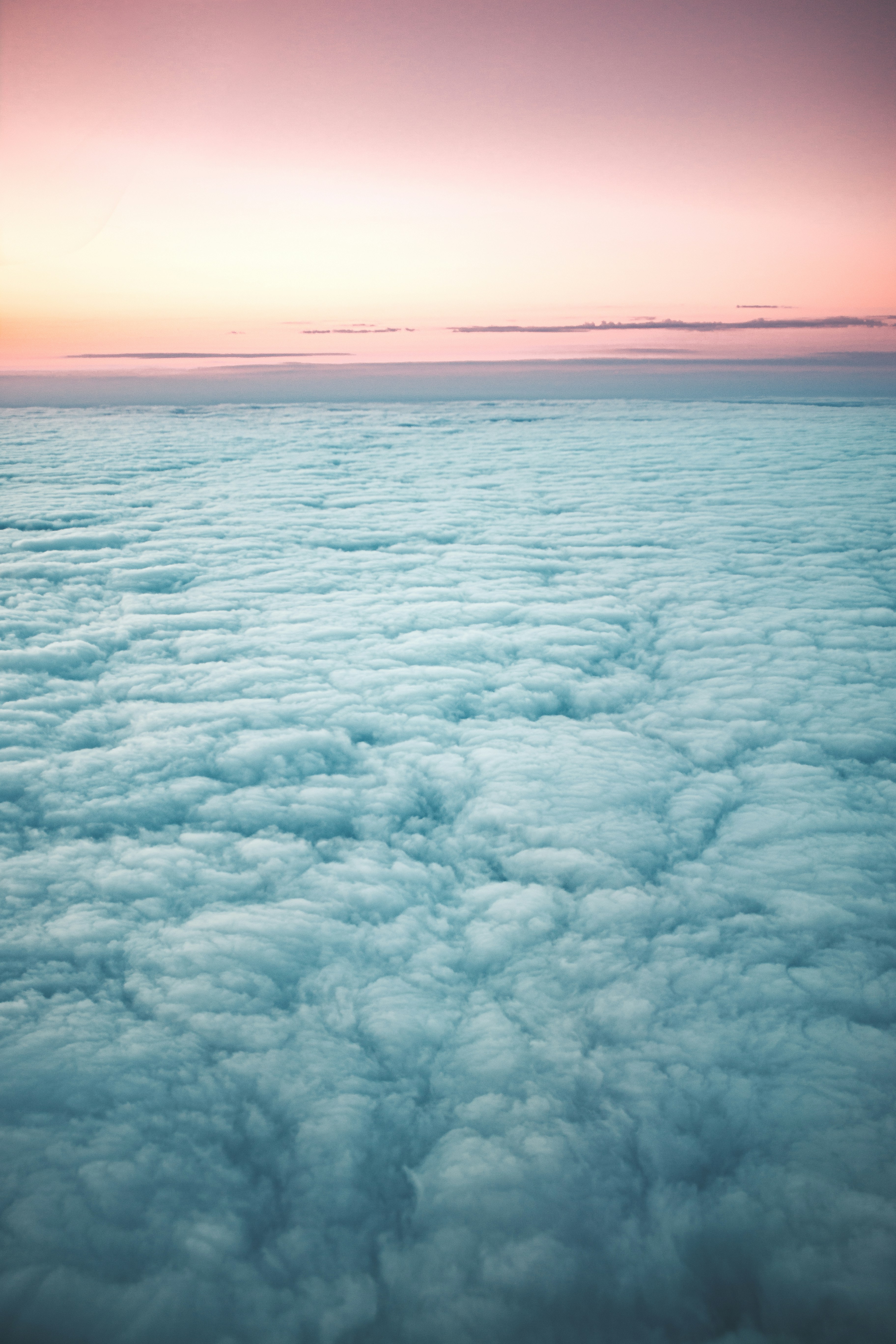 Soft, undulating clouds stretch across the horizon beneath a pastel sky at dusk.