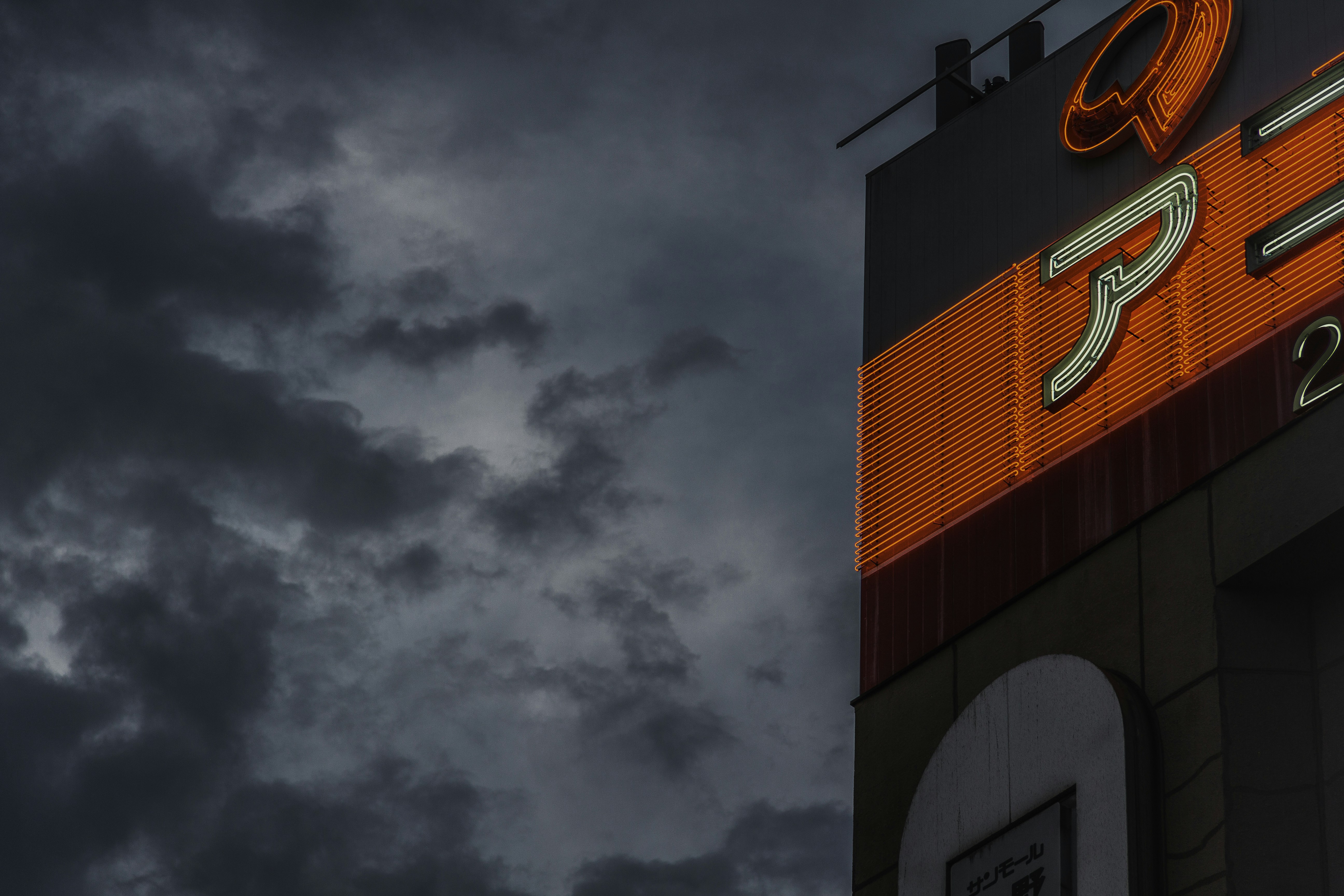 Neon Glyphs on a Cloud-Washed Facade