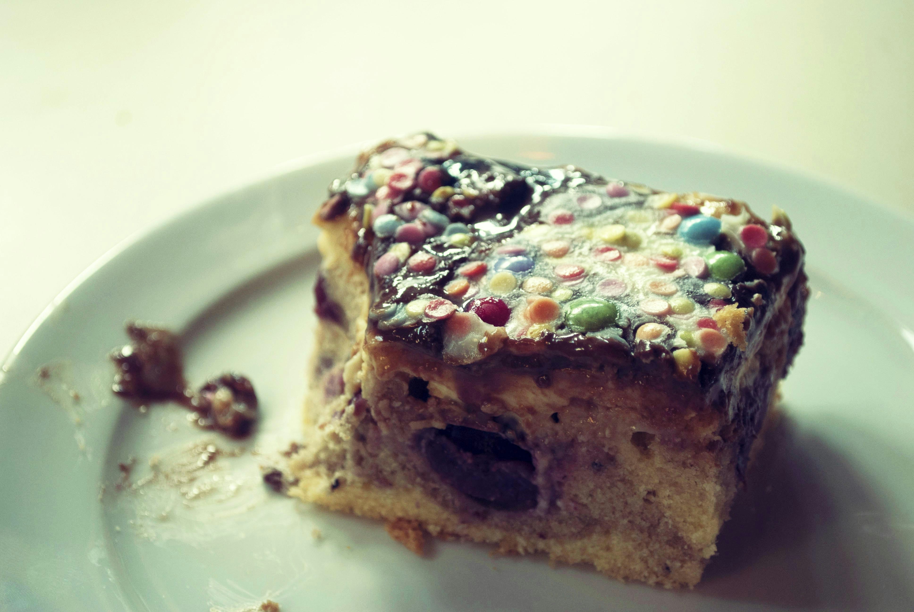 Rainbow-topped dessert slice with glossy glaze on a pale plate