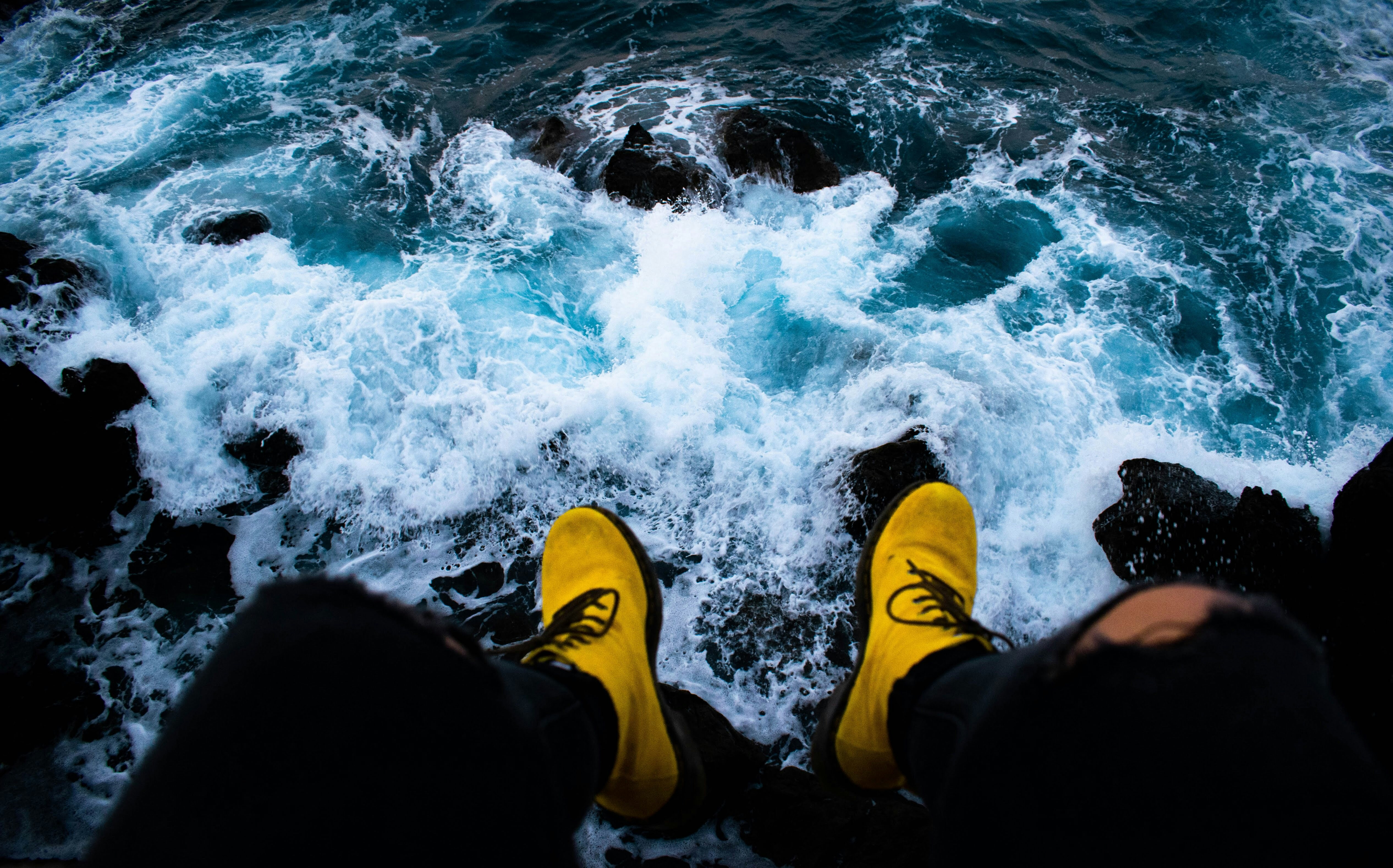Brink Above the Blue: Neon Yellow Boots Hover Over Foamy Ocean