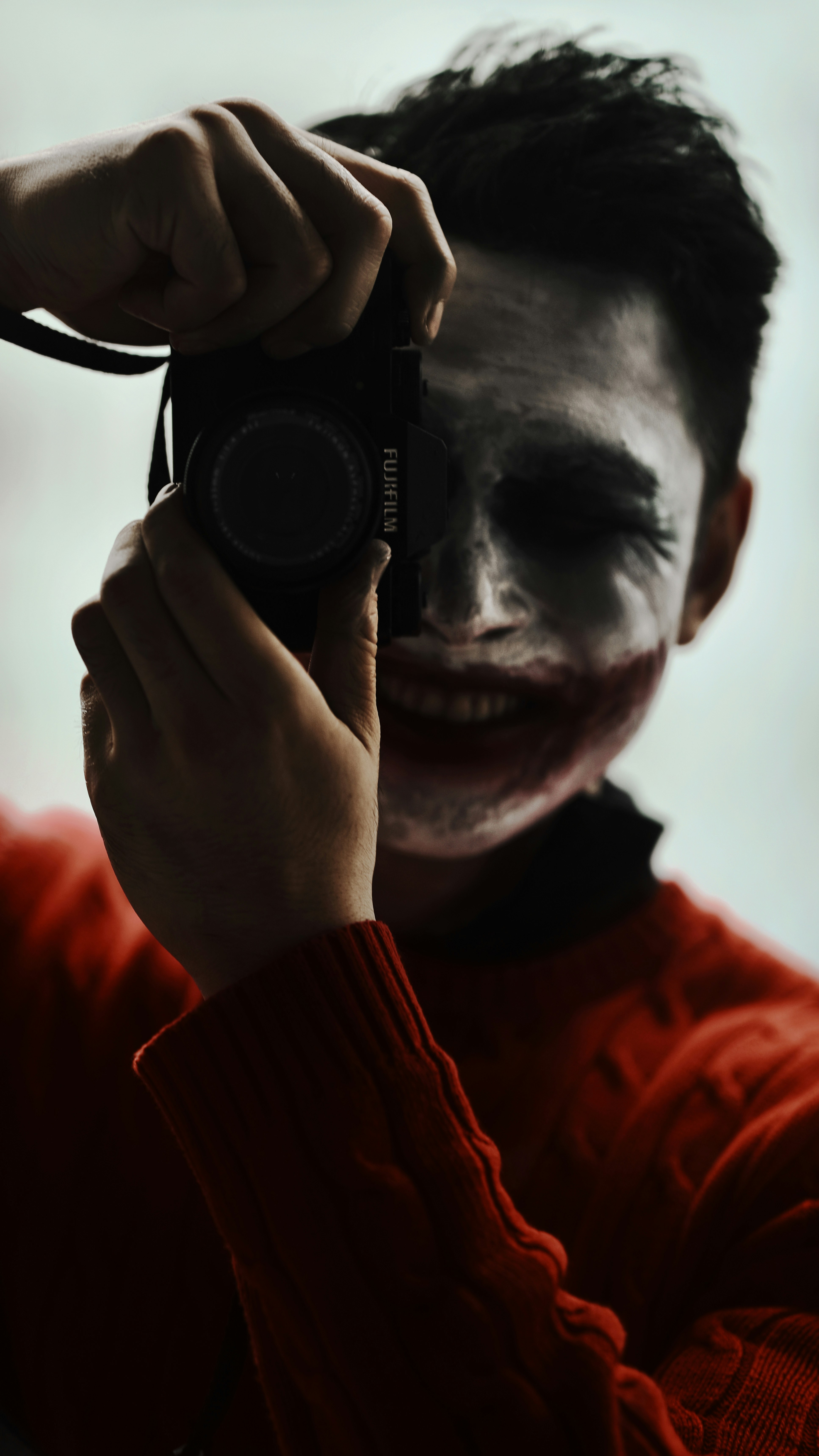 Man holding Fujifilm point-and shoot camera with joker paint on face ...
