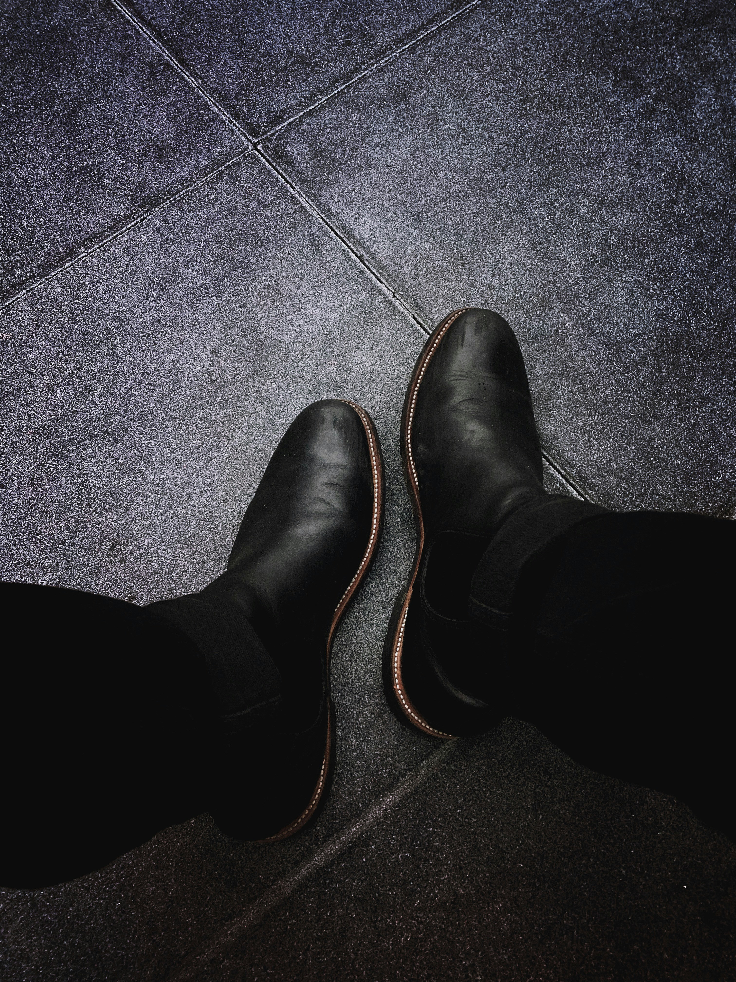 Black leather boots resting on a textured gray surface, showcasing a minimalist aesthetic.
