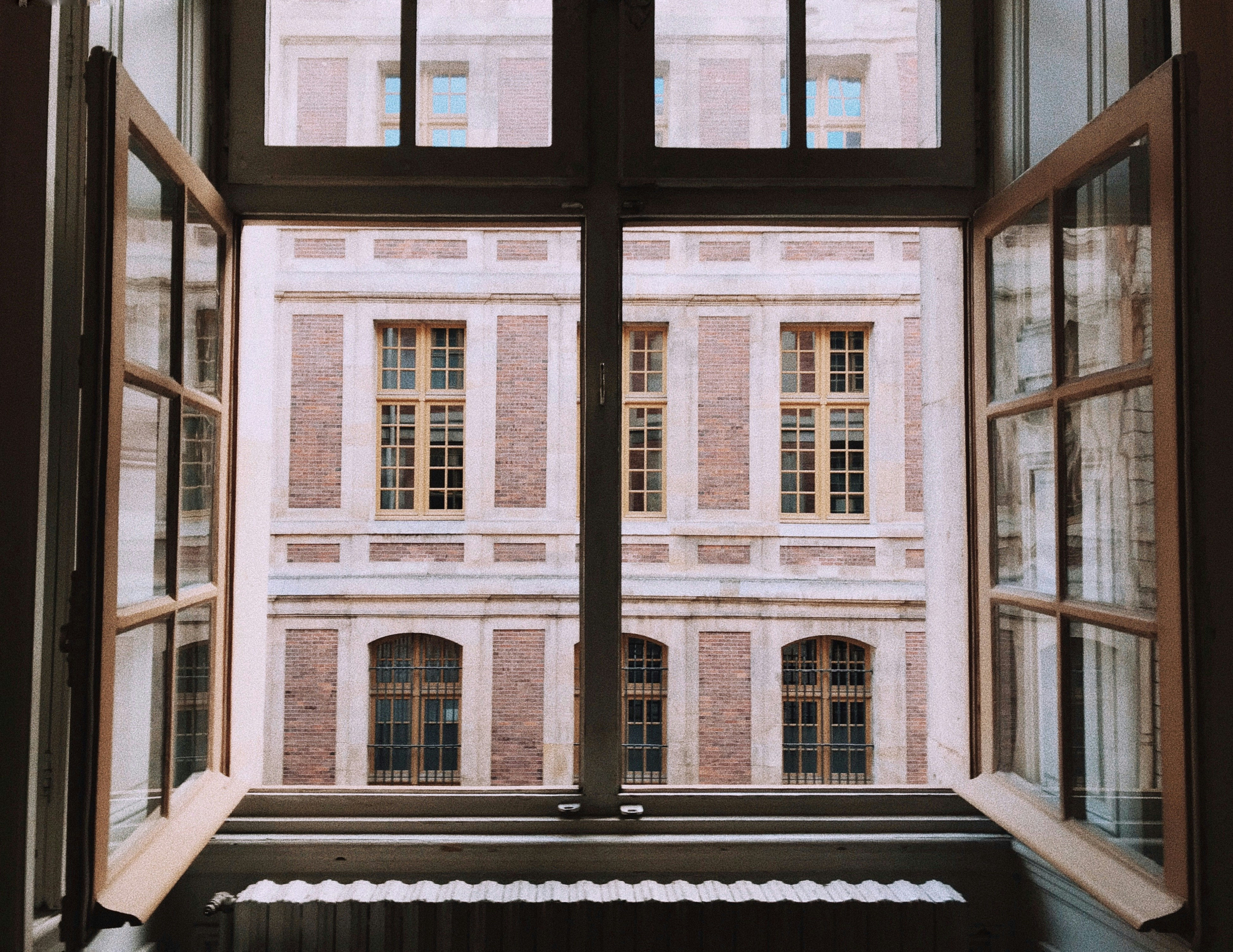 Large window revealing a brick facade with symmetrical window arrangements, showcasing historical architecture and natural light.