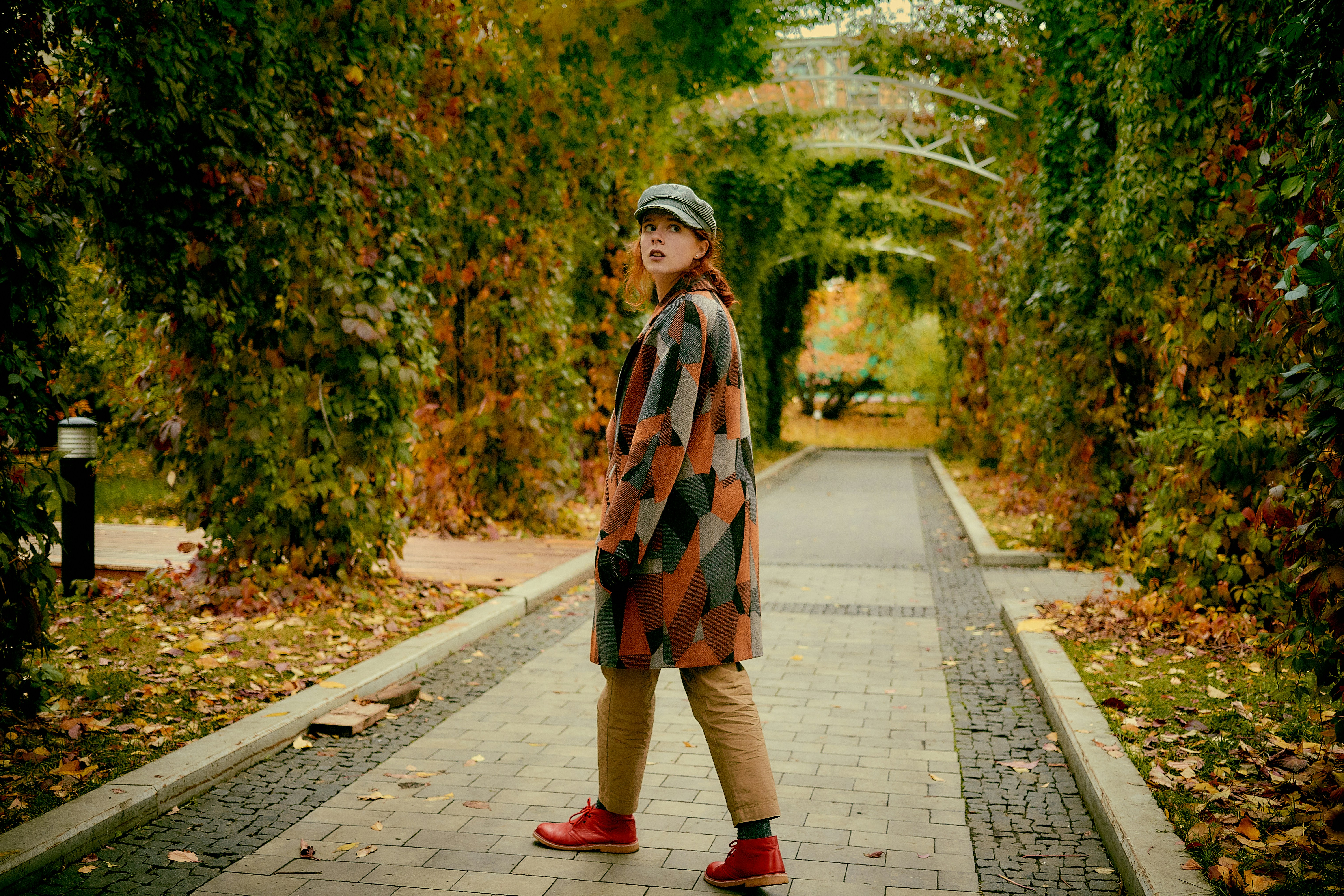 Geometric Coat in a Quiet Autumn Walk Under Arching Vines